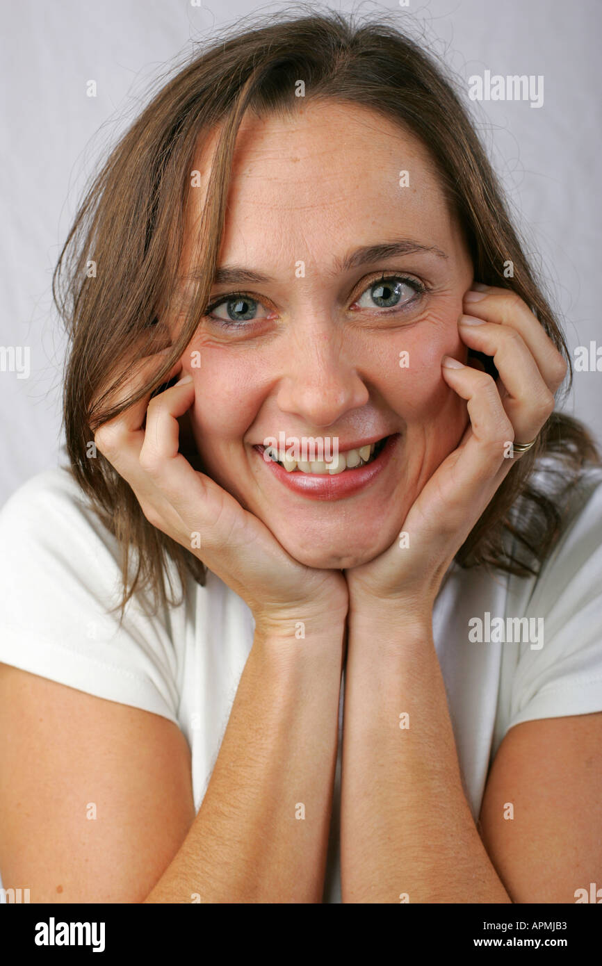 Pretty young brunette woman smiles and laughs with happy contented ...