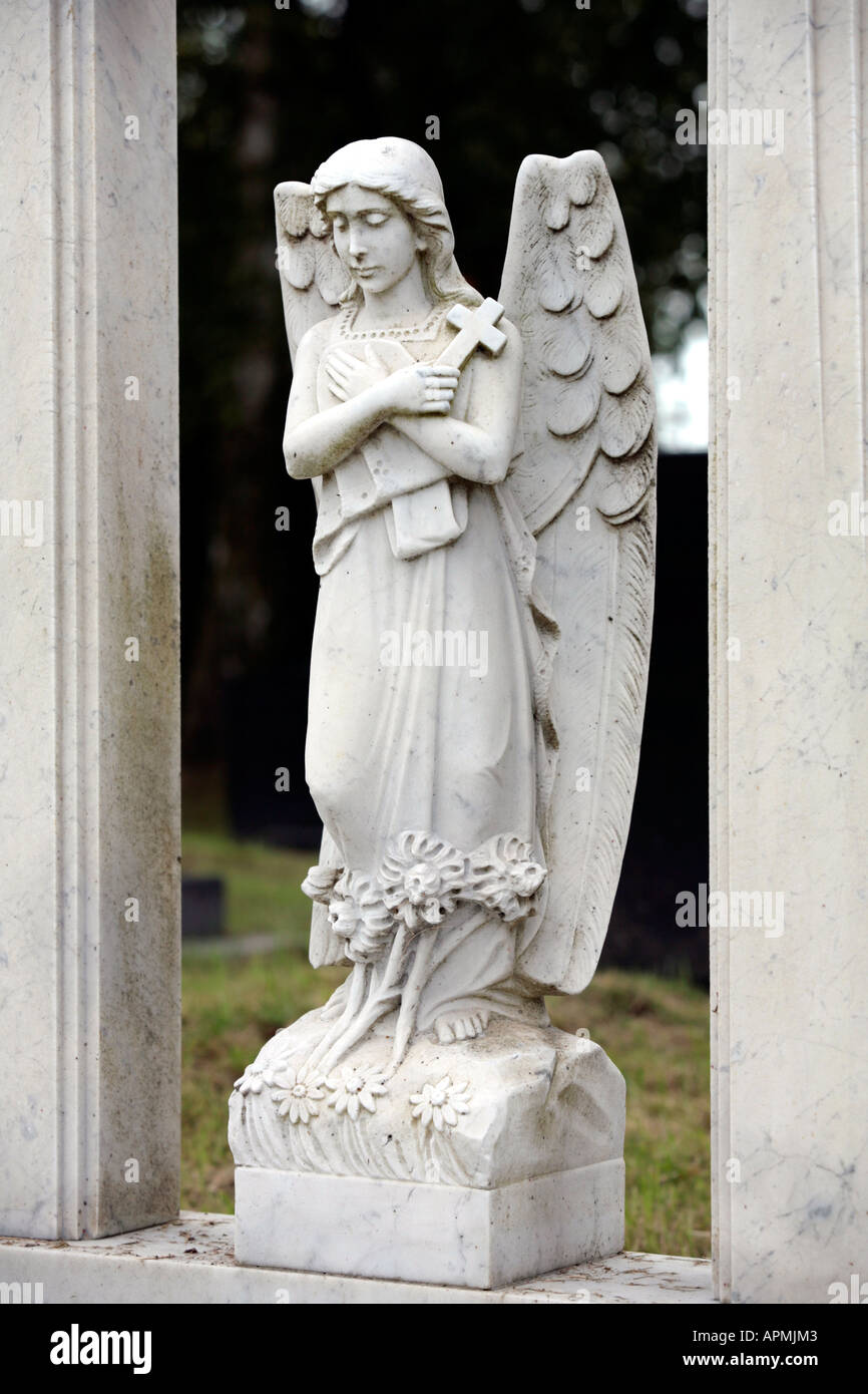 A full length Angel with folded arms carrying a small cross Stock Photo ...