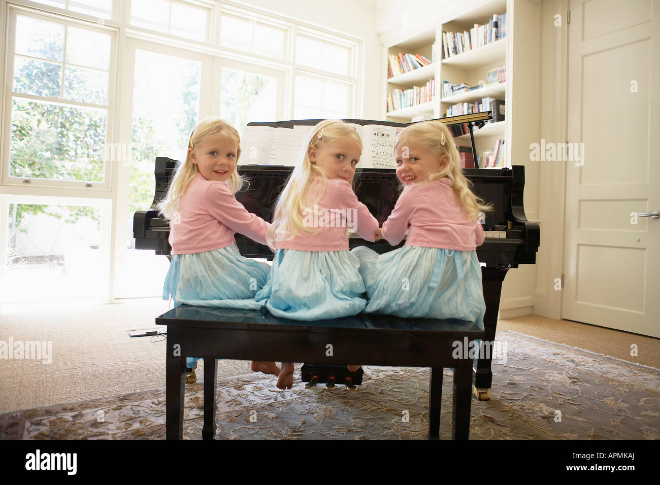 Triplets playing piano in living room (rear view Stock Photo - Alamy
