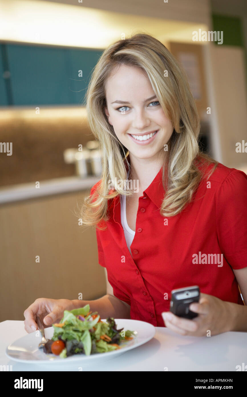 Young woman using cell phone while having lunch Stock Photo - Alamy
