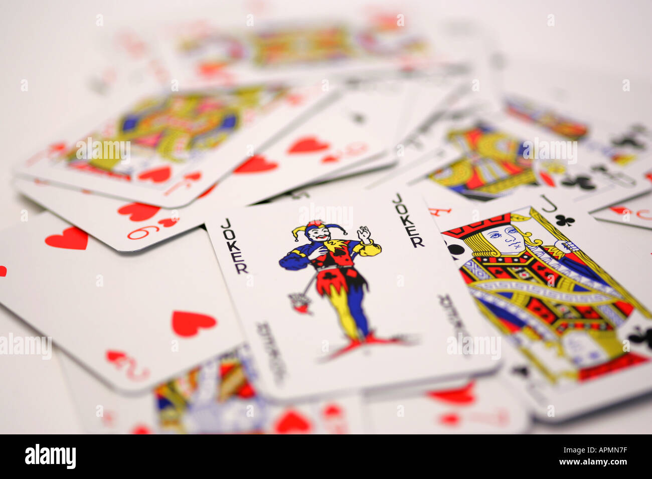 Narrow field of focus on a Joker playing card lying on top of a messy ...