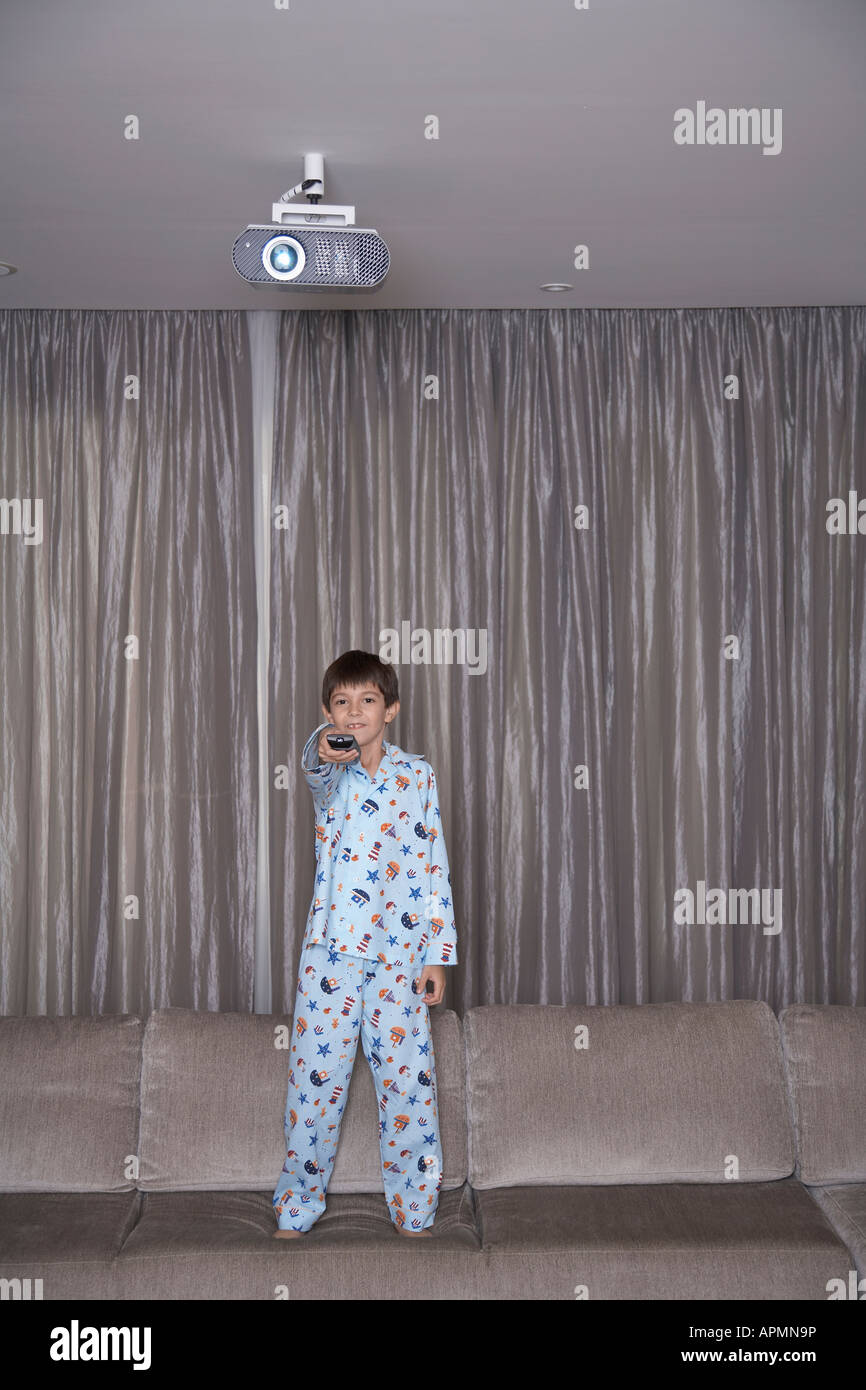 Boy standing on sofa and using remote control Stock Photo - Alamy