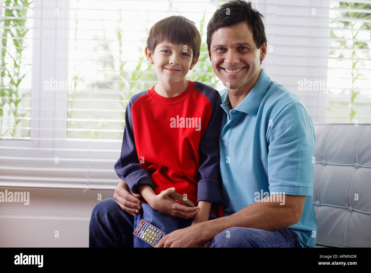 Father and son sitting on armchair, father holding remote control Stock ...