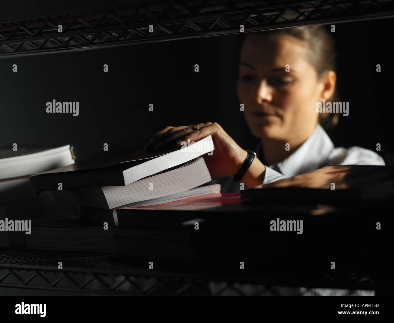 Office worker looking through a stack of books Stock Photo - Alamy