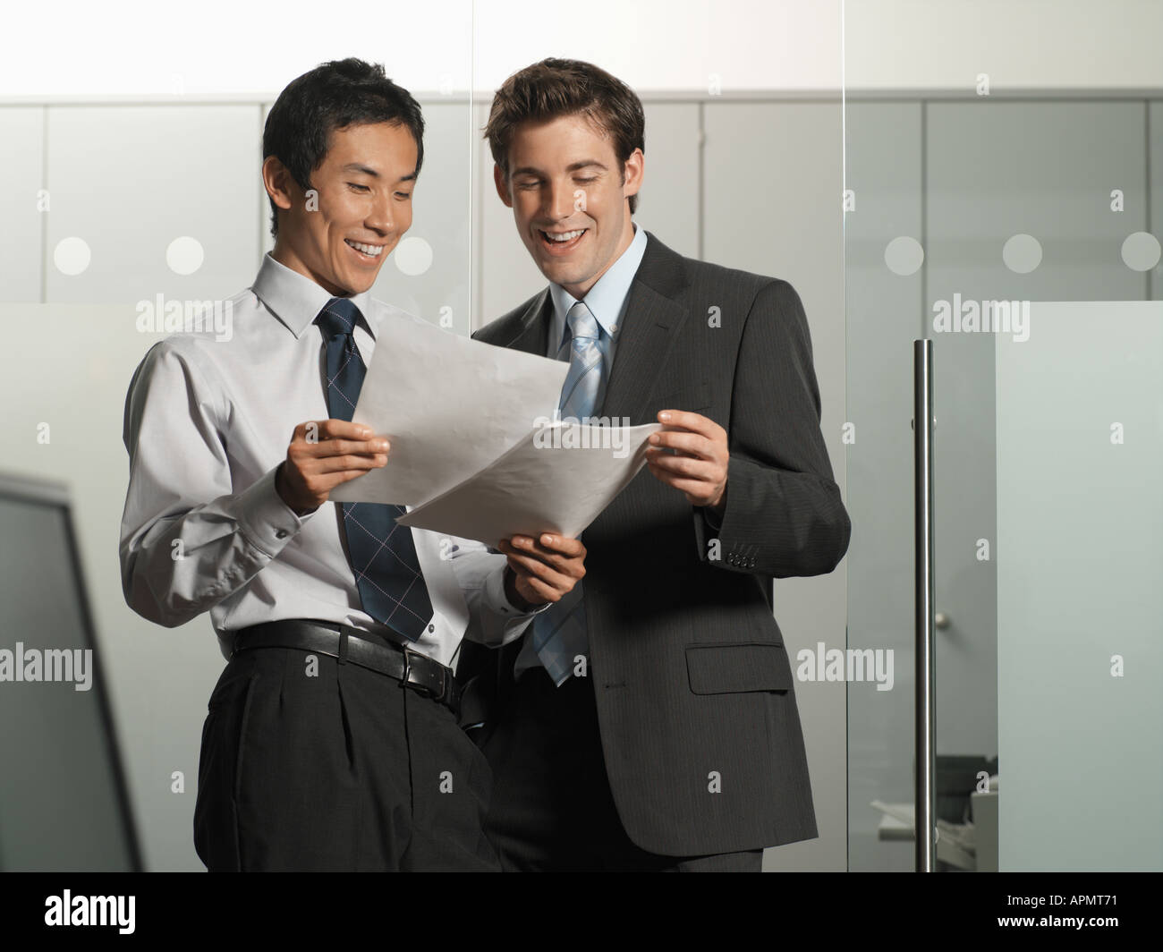 Colleagues smiling at paperwork Stock Photo - Alamy