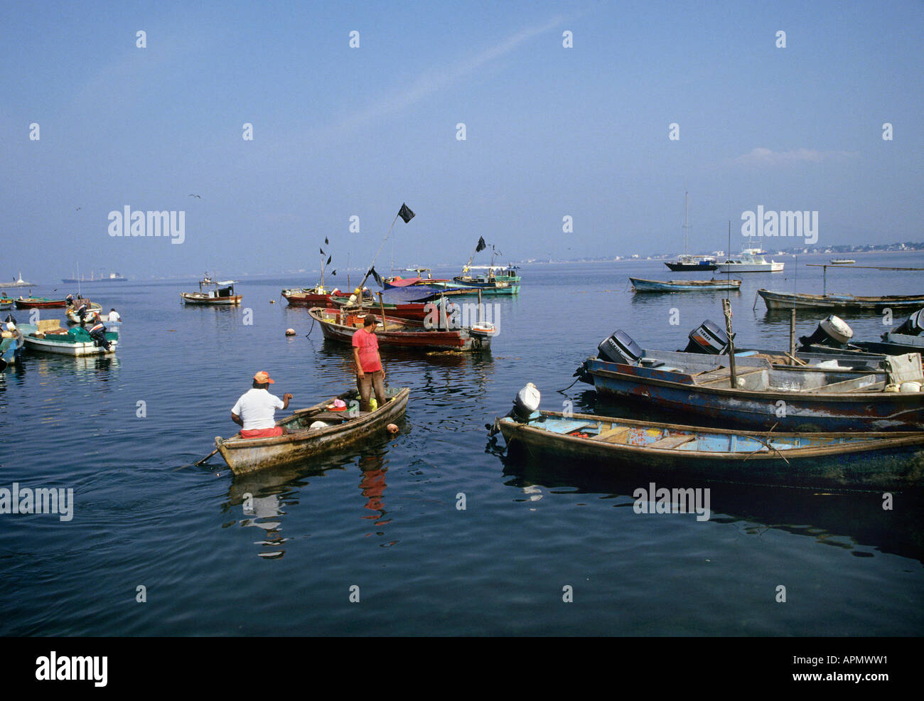 Two fisherman guide their small vessel between the boats which lie ...