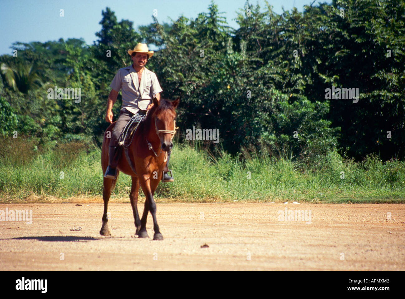 A Mexican ranchero wearing a cowboy hat and crossing a bare patch of ...