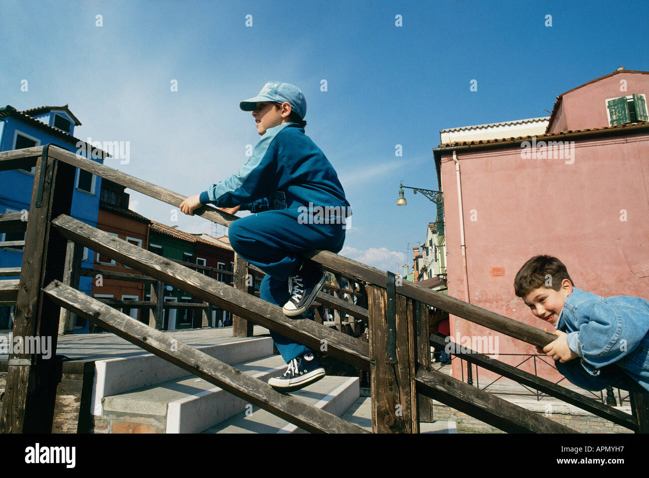 Two young boys sliding down the handrail bordering a flight of steps in ...
