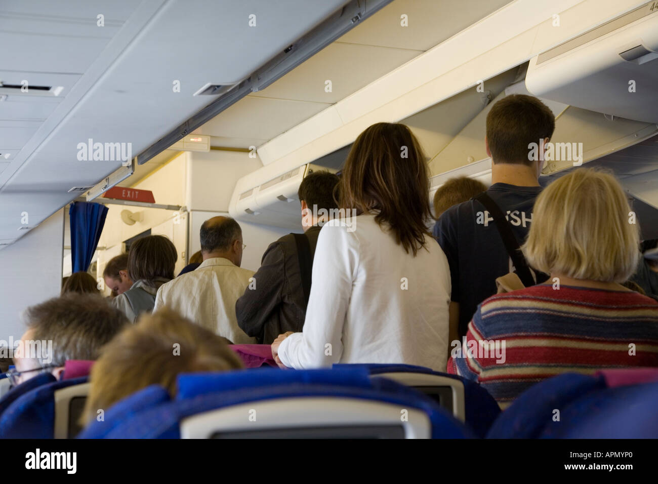 Travellers standing in aisle waiting to leave plane at Heathrow airport ...