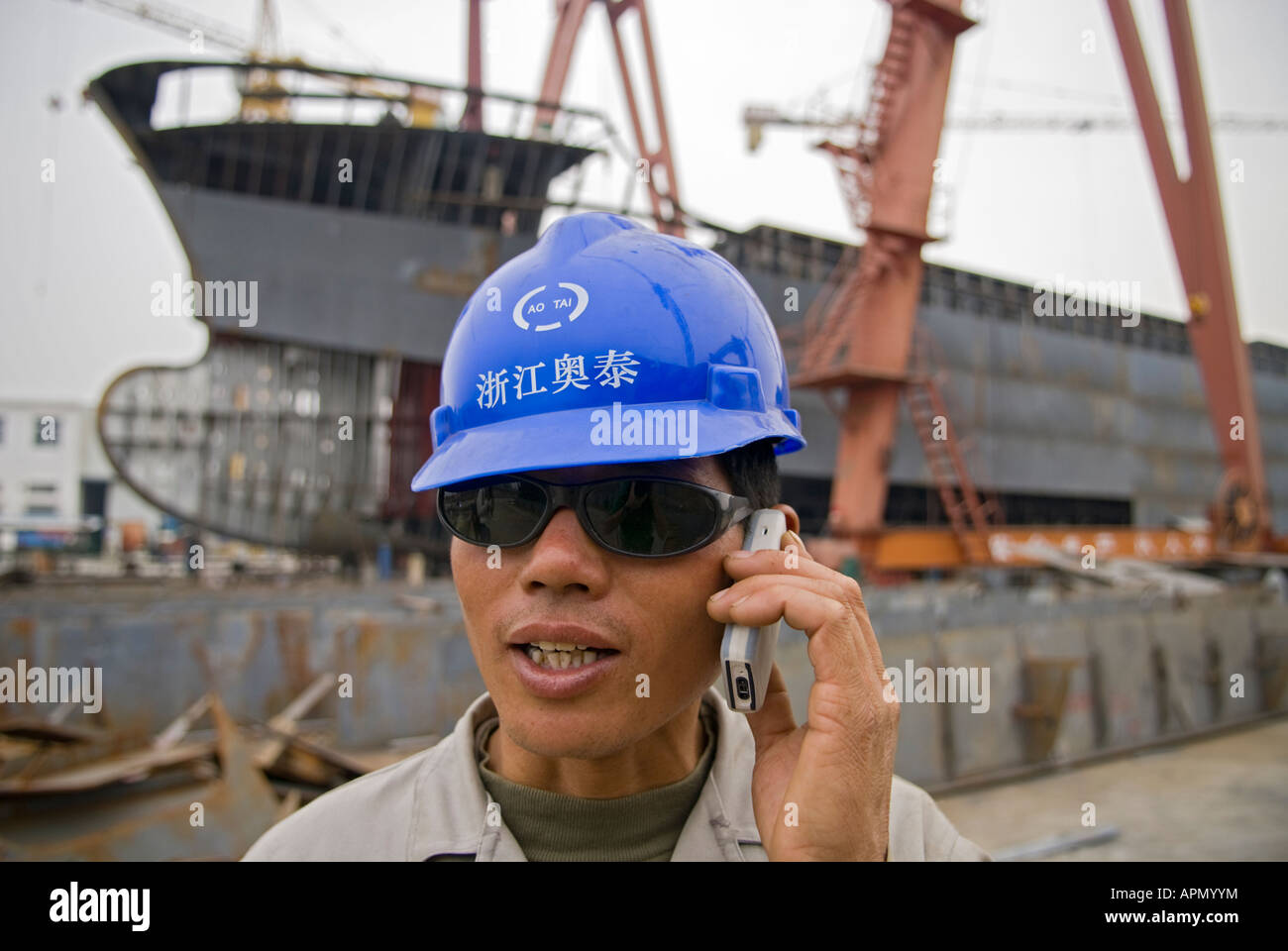 Ship yard foreman speaks on cellular telephone, Aotai Ship ...