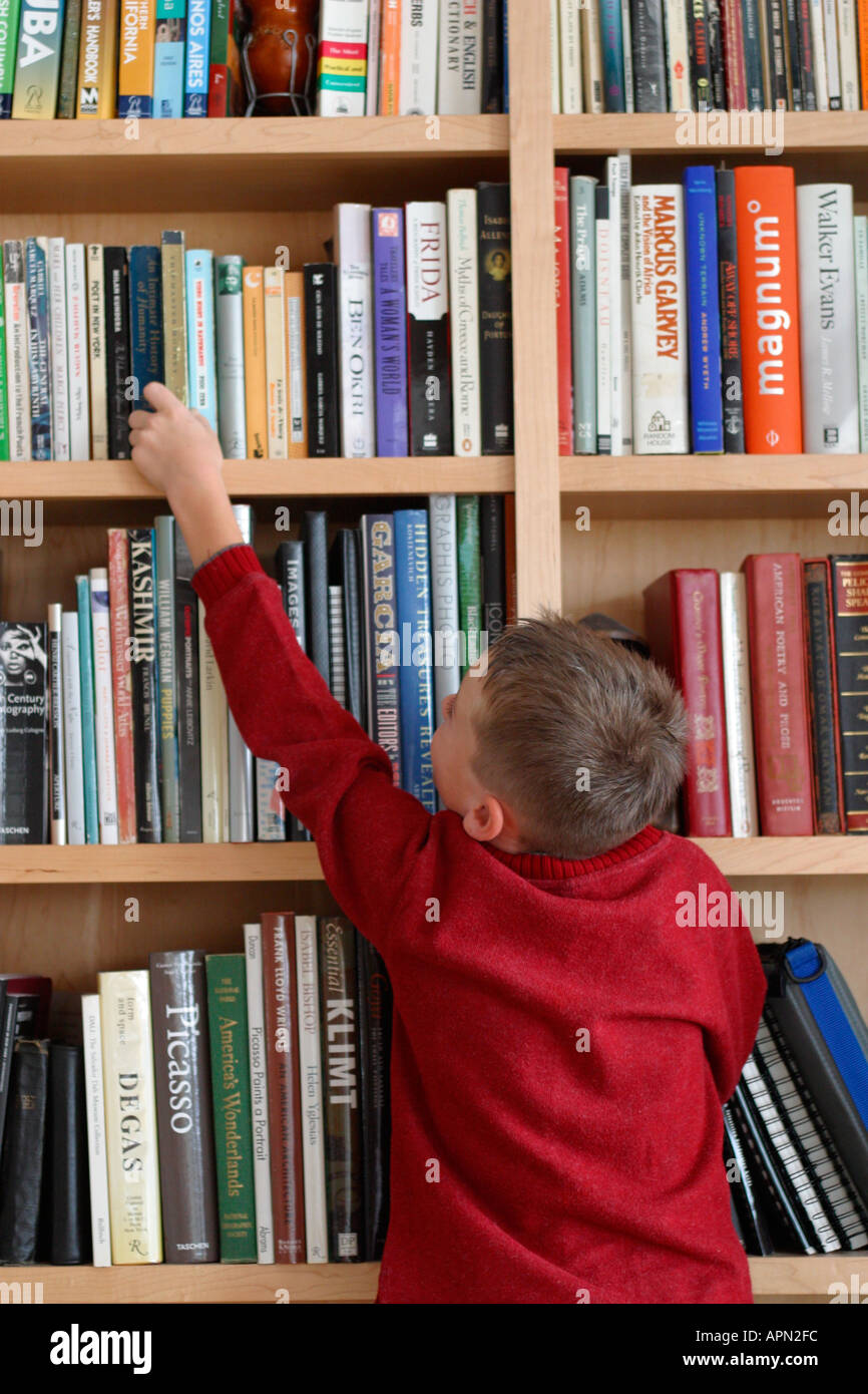 Boy Reaching for Book Stock Photo - Alamy