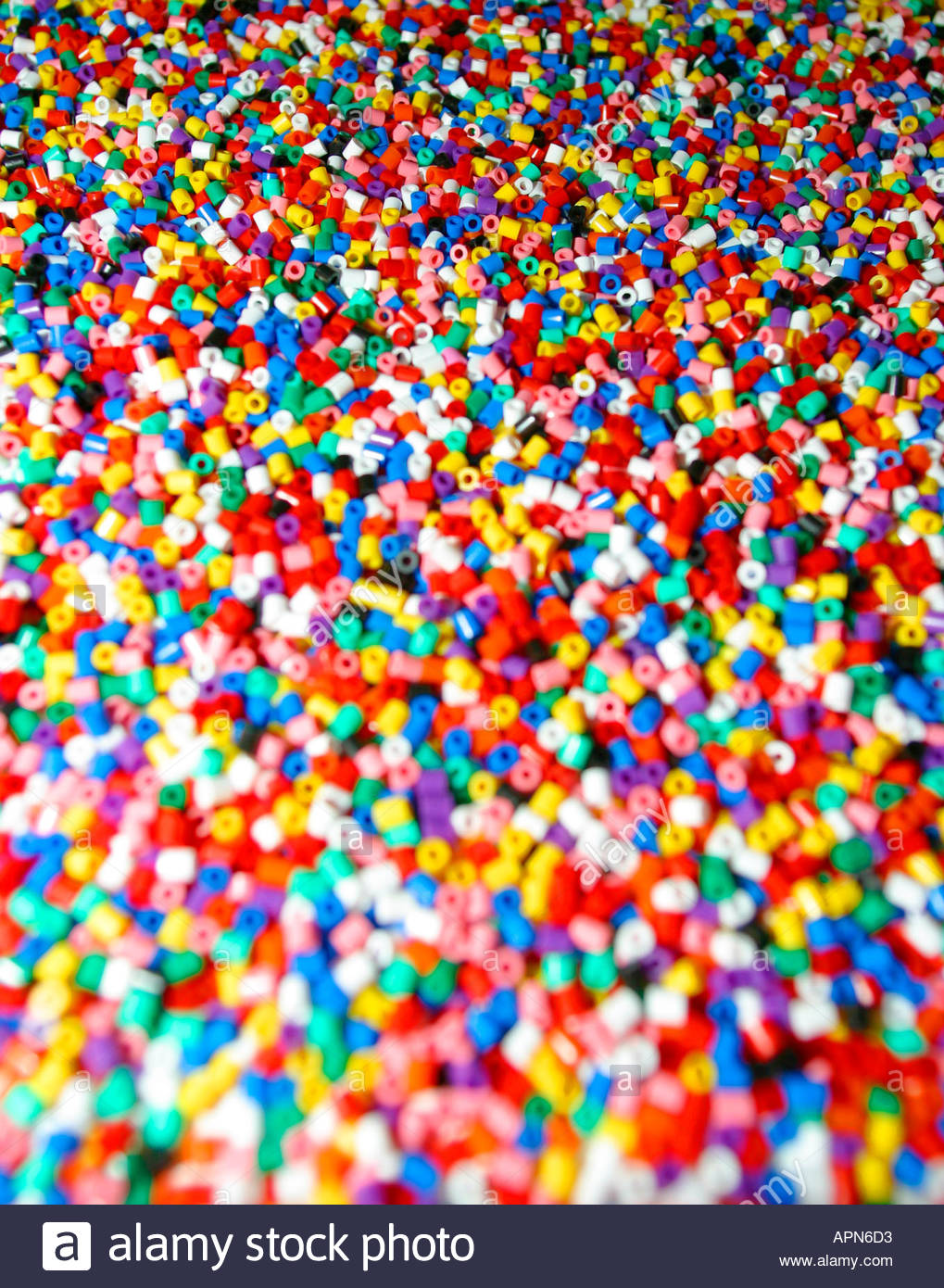 Childrens multi coloured craft beads spread out to form background ...