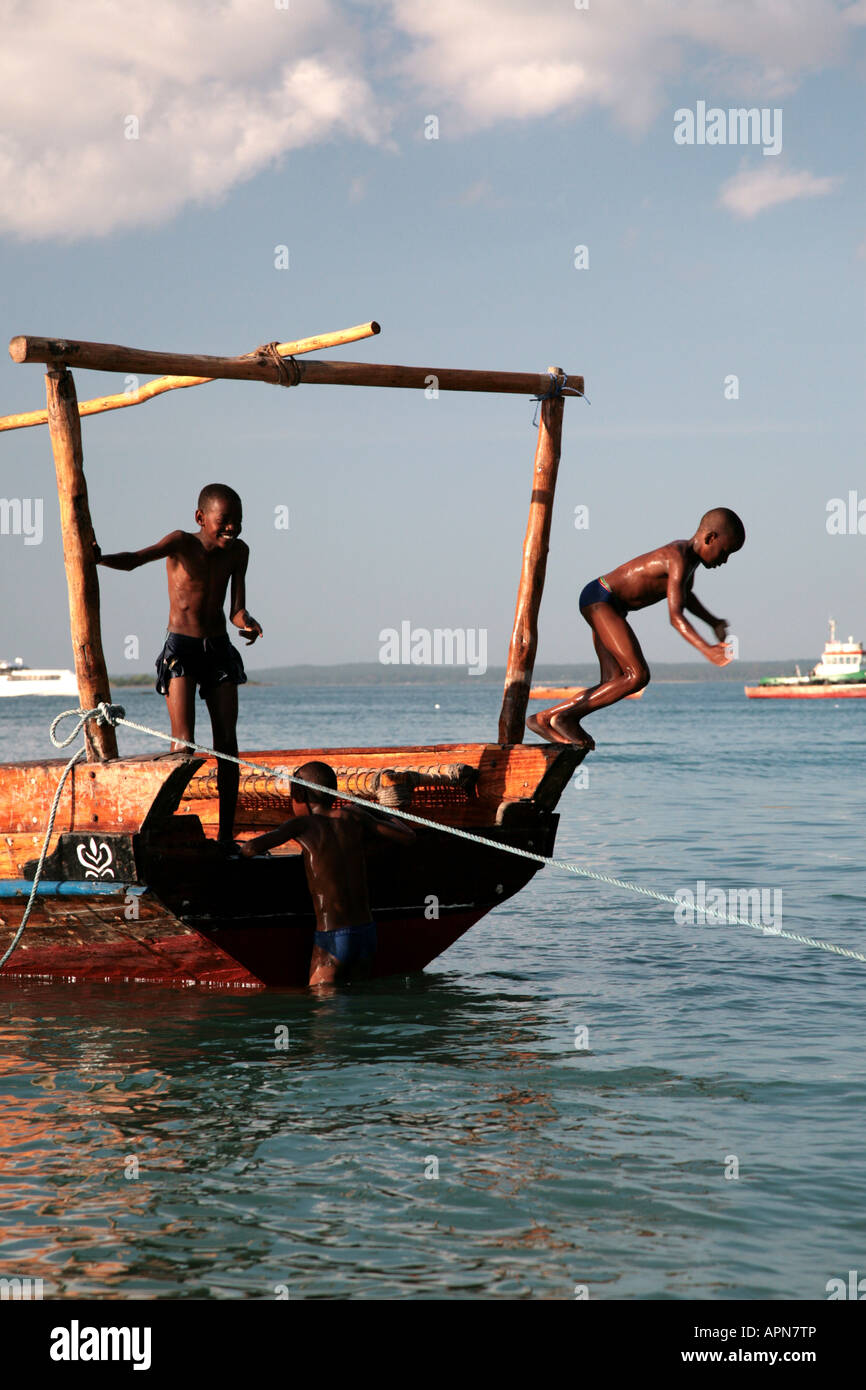 Children diving and playing on a traditional sailing dhow off the coast ...