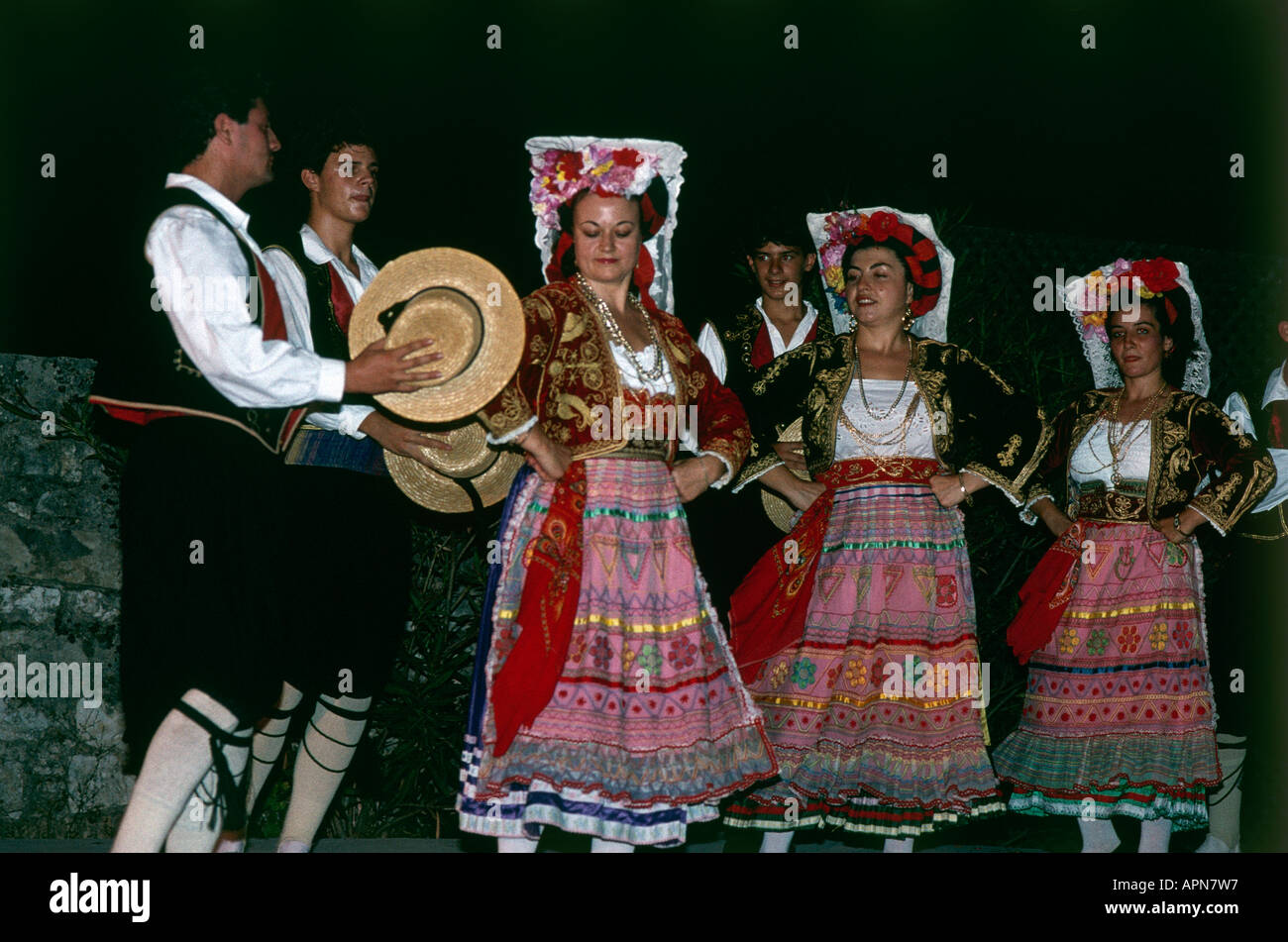 Greek men and women traditionally dressed dancing by torchlight at a ...