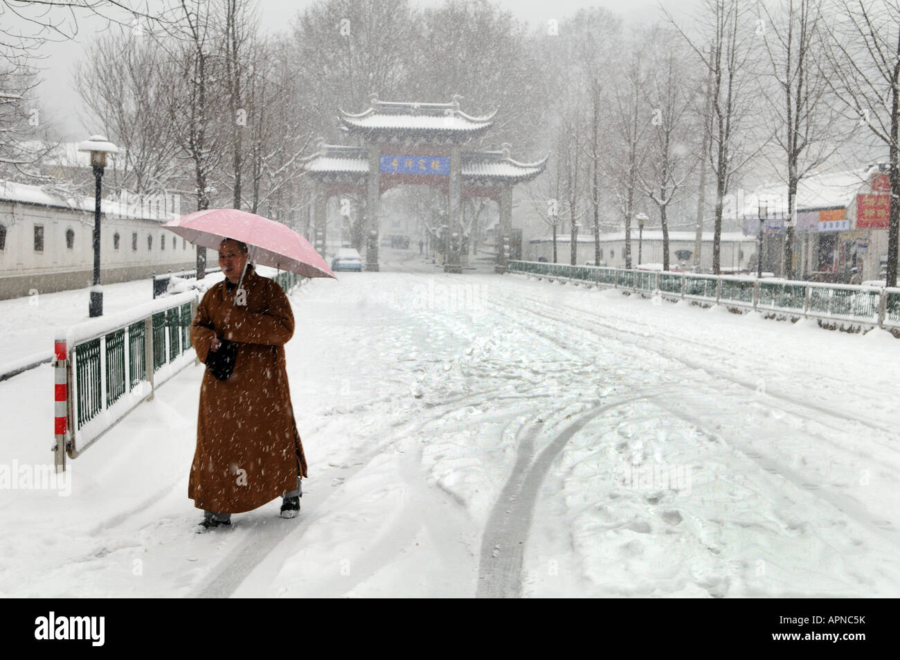 A Chinese Buddhist monk walking in a snow storm at the Qi Xia monastery ...