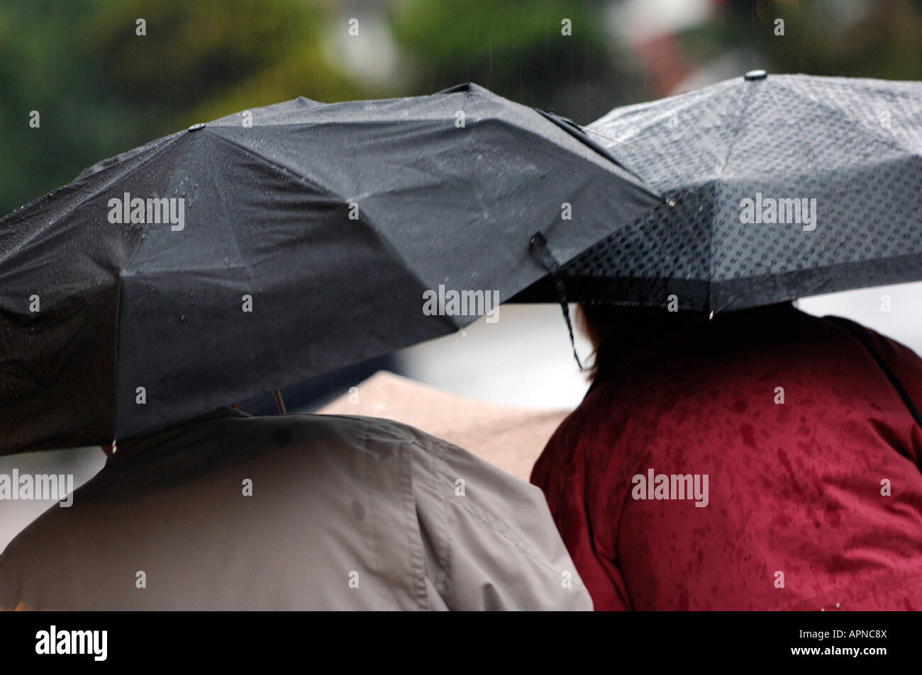 tow people walking in the rain wearing waterproofs clothing and holding ...