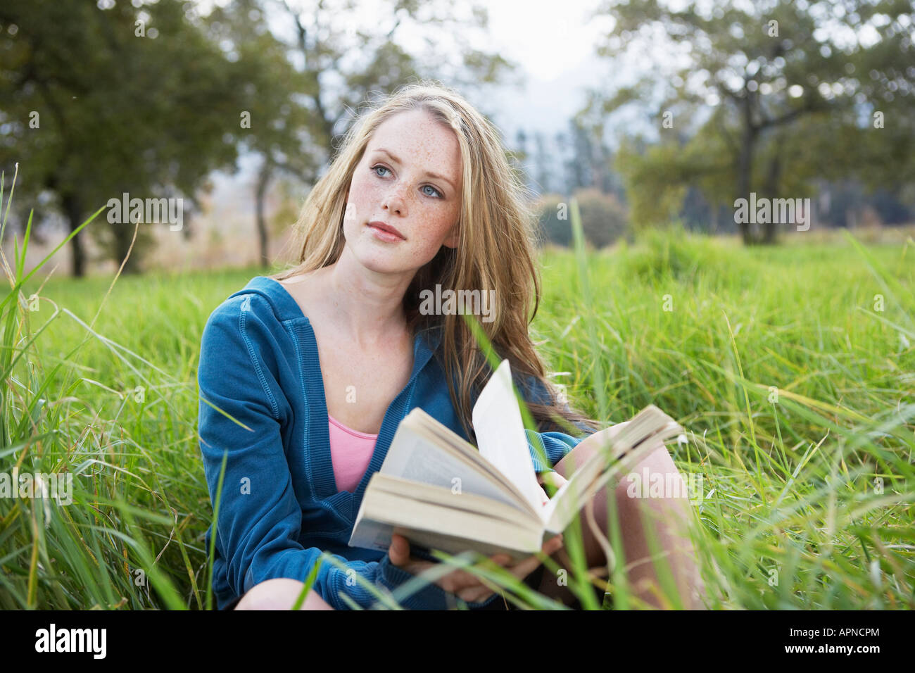 Teenage girl reading book in field Stock Photo - Alamy