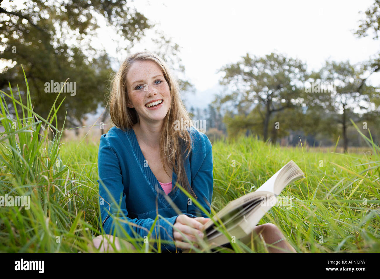 Teenage girl reading book in field Stock Photo - Alamy