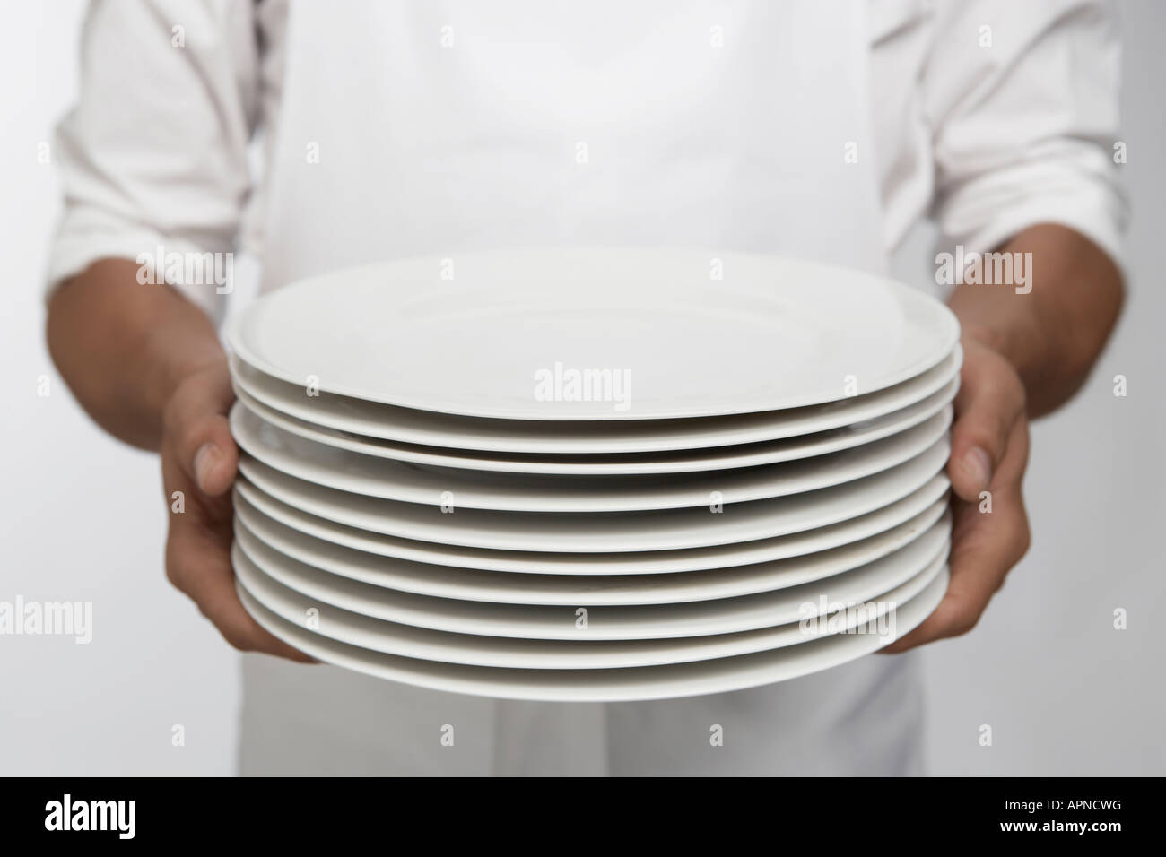Chef holding stack of dinner plates (mid section Stock Photo - Alamy