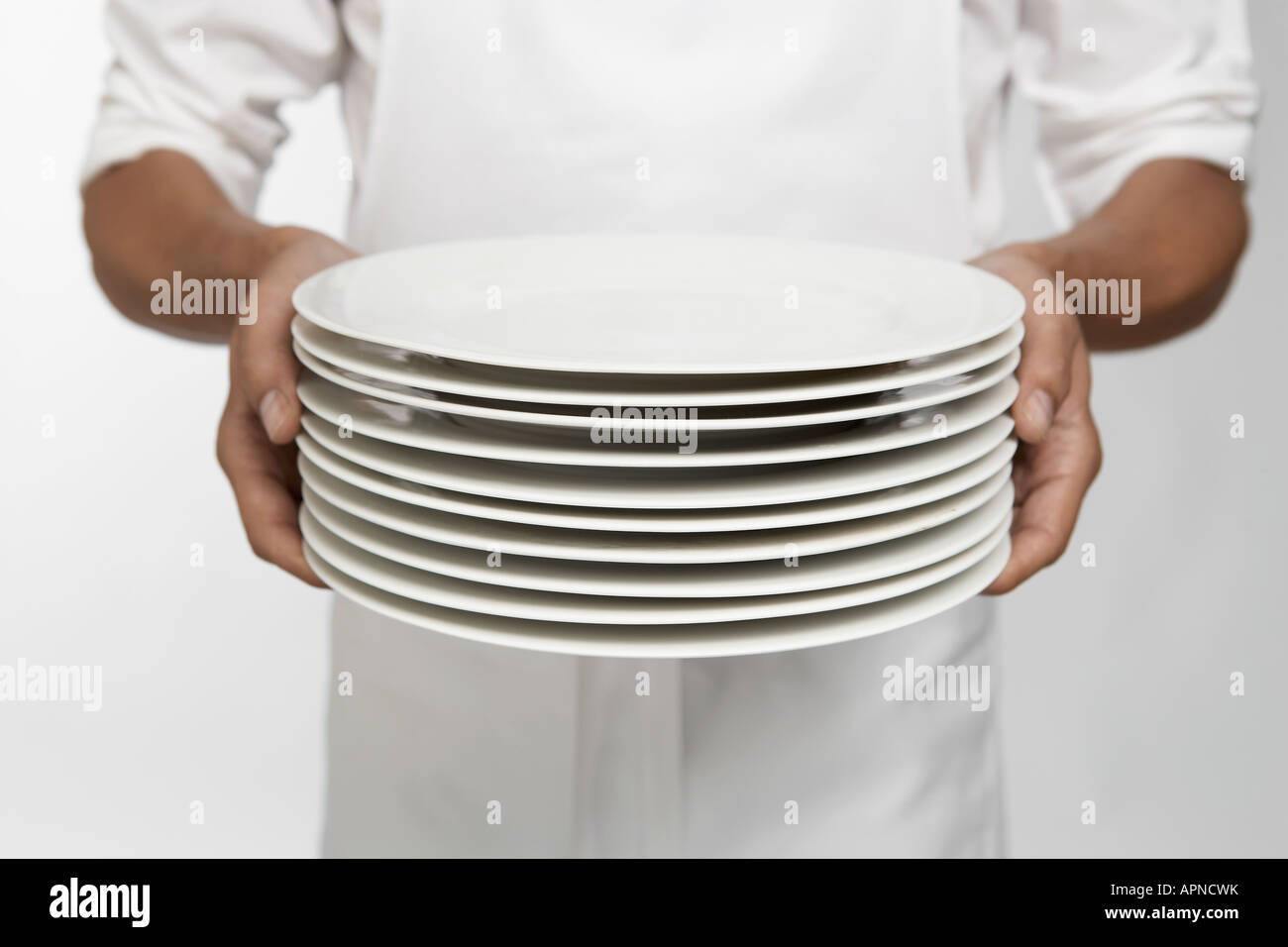 Chef holding stack of dinner plates (mid section Stock Photo - Alamy