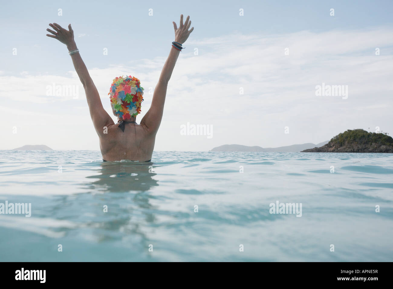Young woman raising hands in ocean at dusk, St John, US Virgin Islands ...