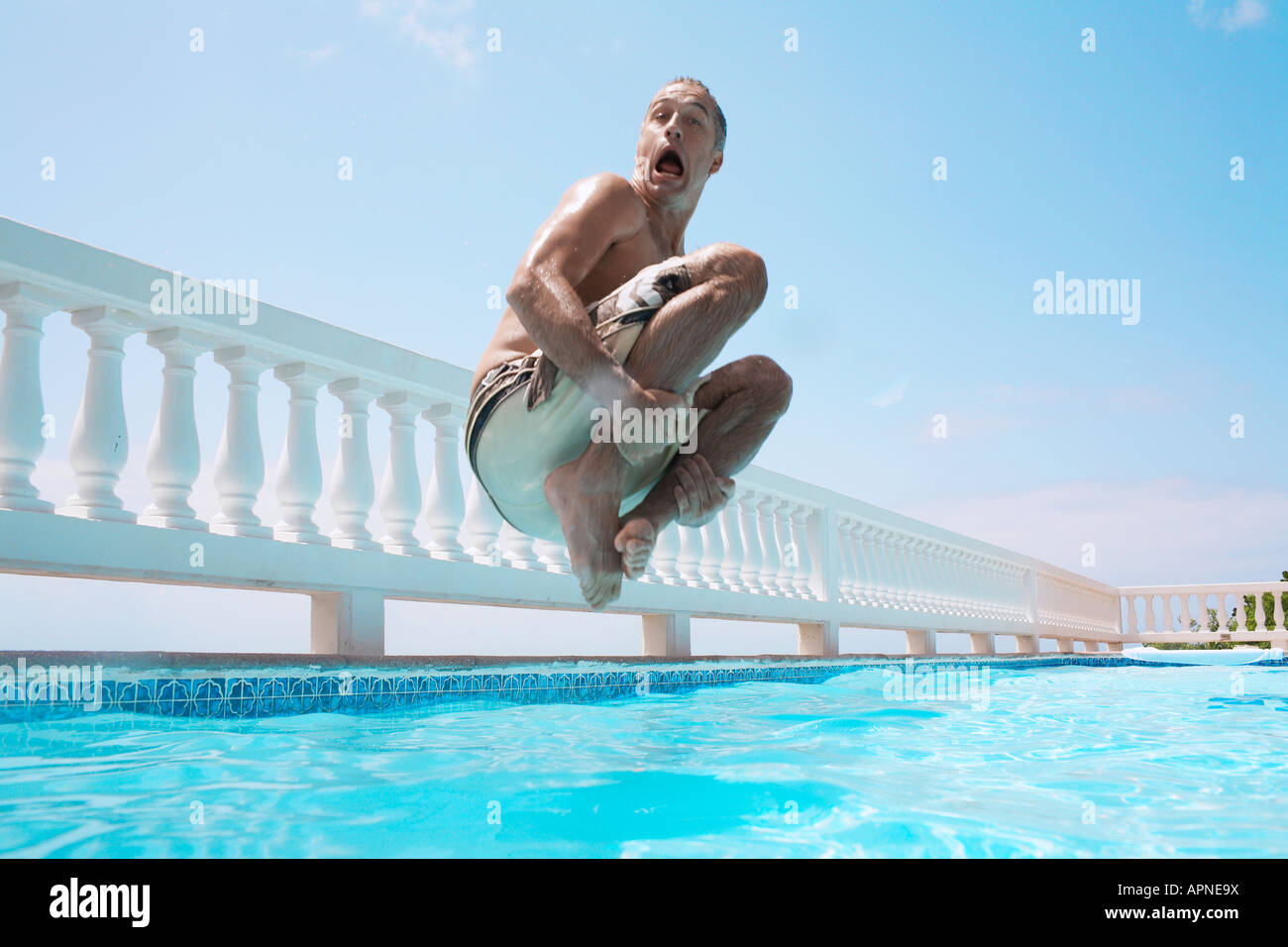Mid adult man jumping into swimming pool Stock Photo - Alamy