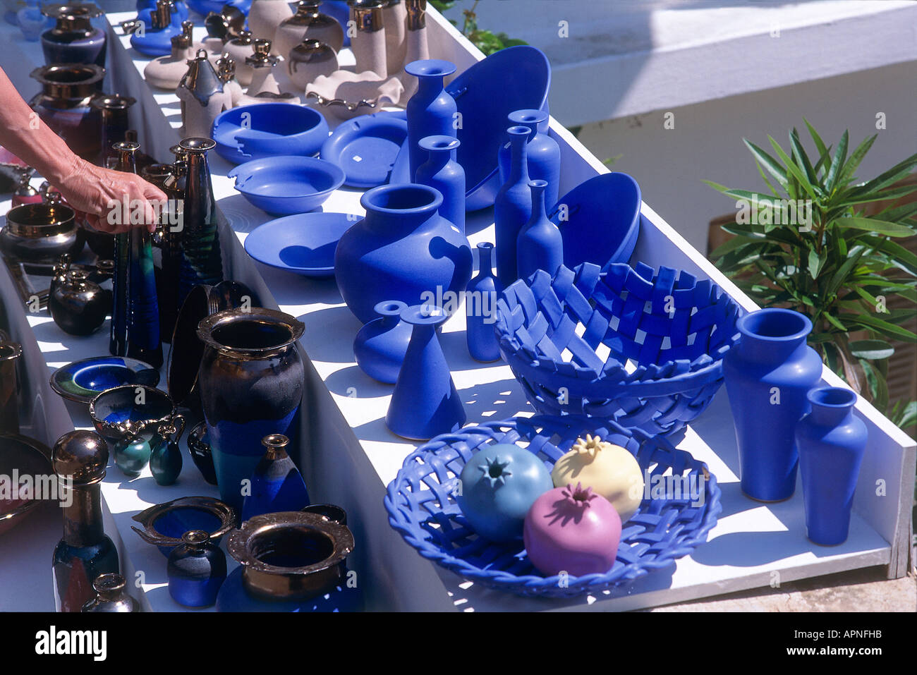 A display of glazed blue pottery on a stall in a market in the village ...