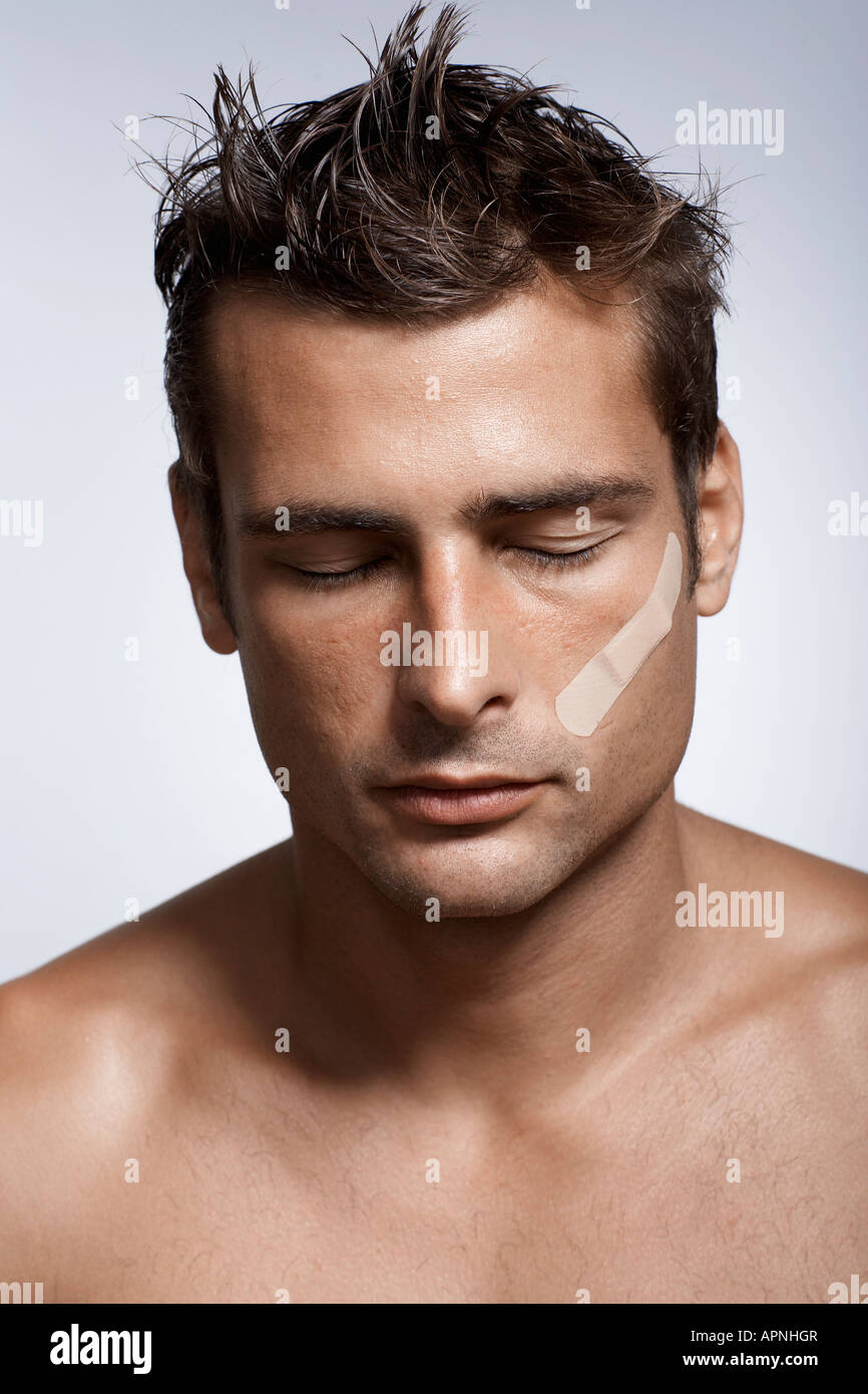 Mid adult man with adhesive plaster on cheek Stock Photo - Alamy