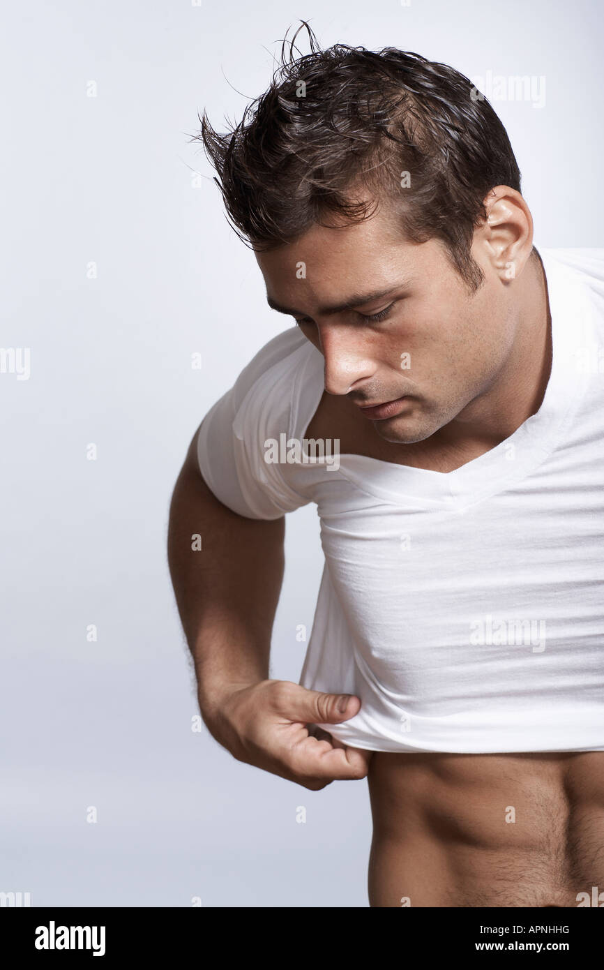 Mid adult man putting T-shirt on Stock Photo - Alamy