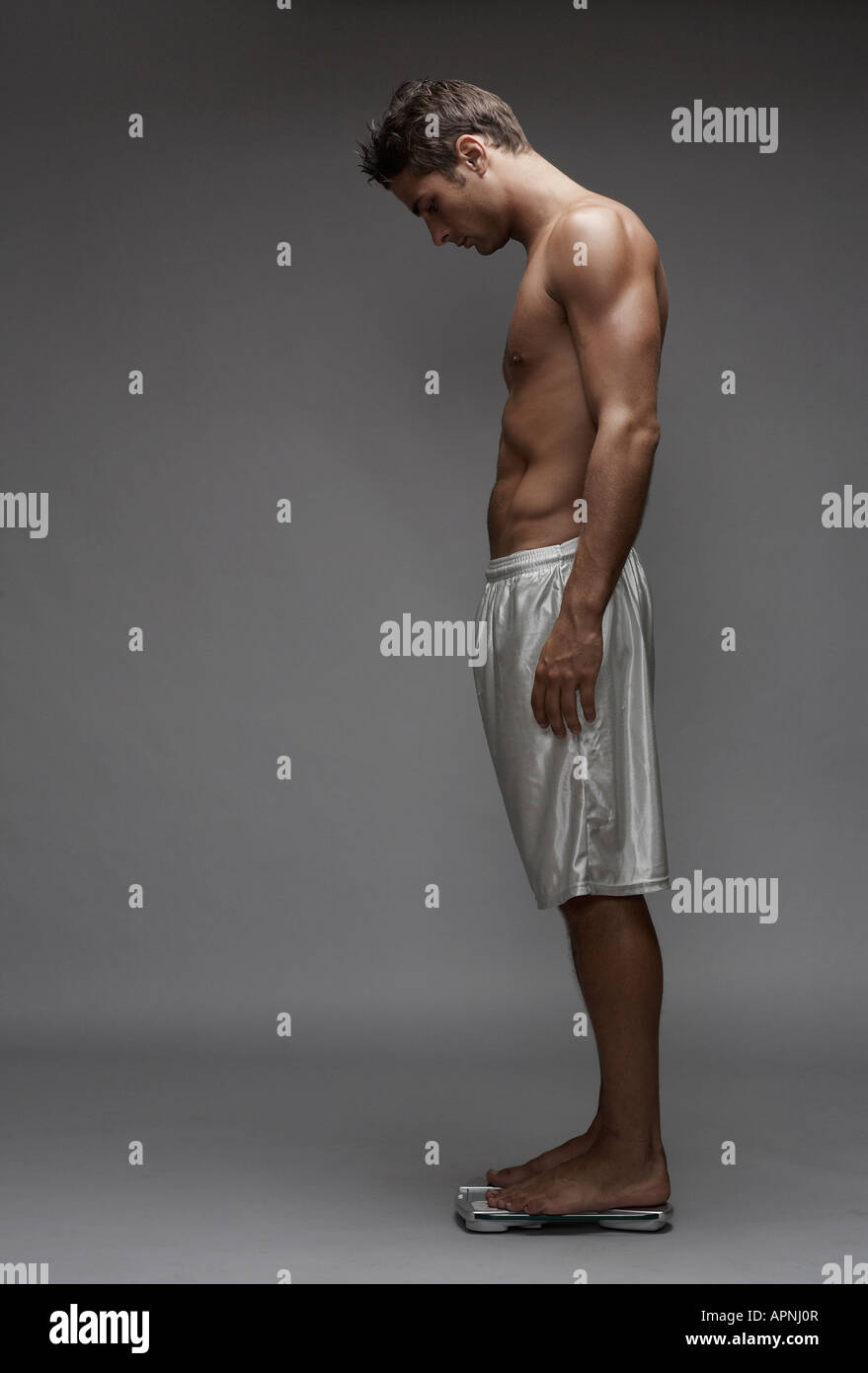 Mid adult man standing on weight scale Stock Photo - Alamy