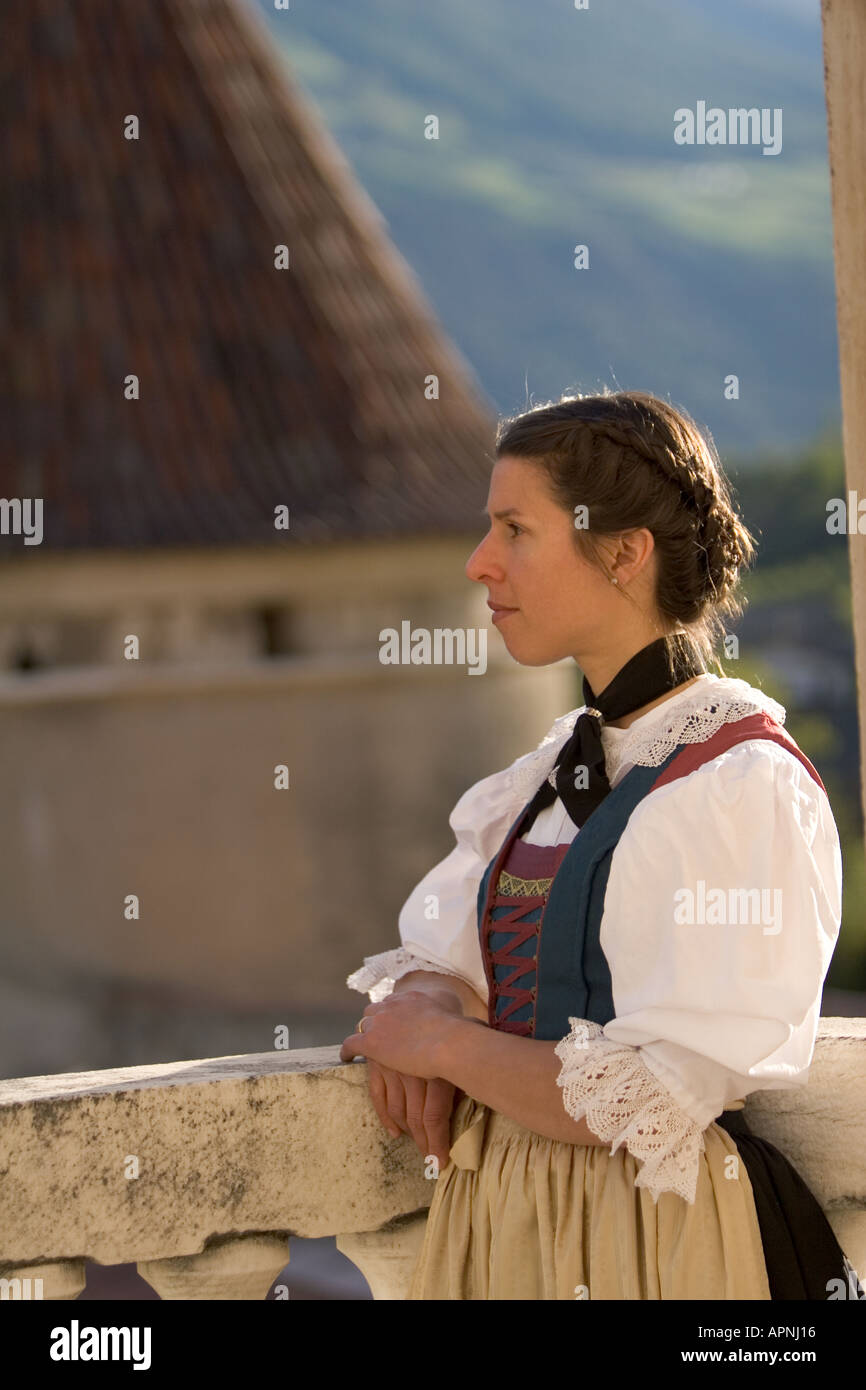 Young woman in Tyrolean costume stands on balcony with a tower of ...