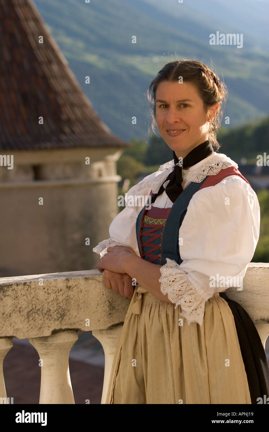 Young woman in Tyrolean costume stands on balcony with a tower of ...