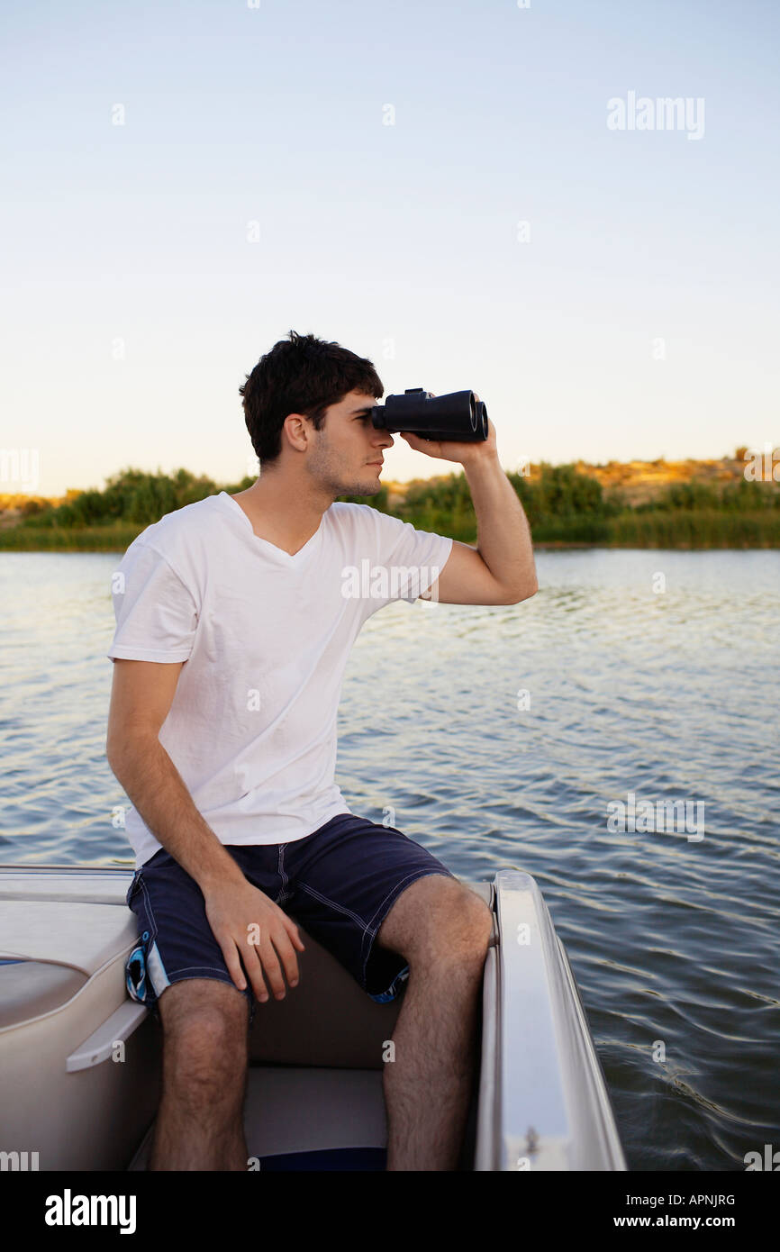 Young man using binoculars at lake Stock Photo - Alamy