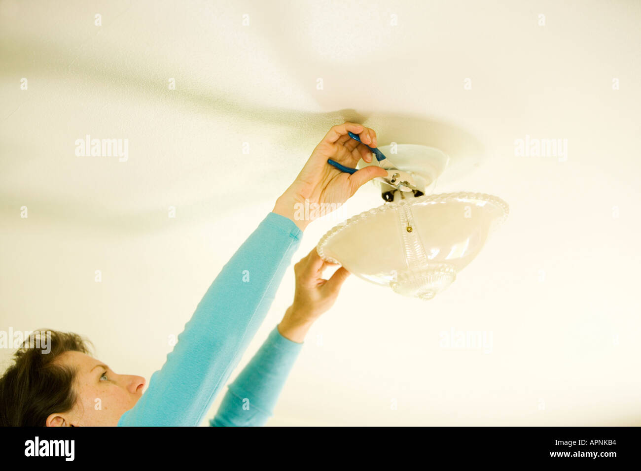 Woman repairing lighting fixture on ceiling Stock Photo - Alamy