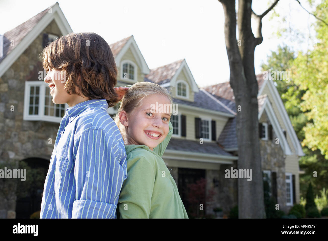 Sister and brother standing back to back Stock Photo - Alamy
