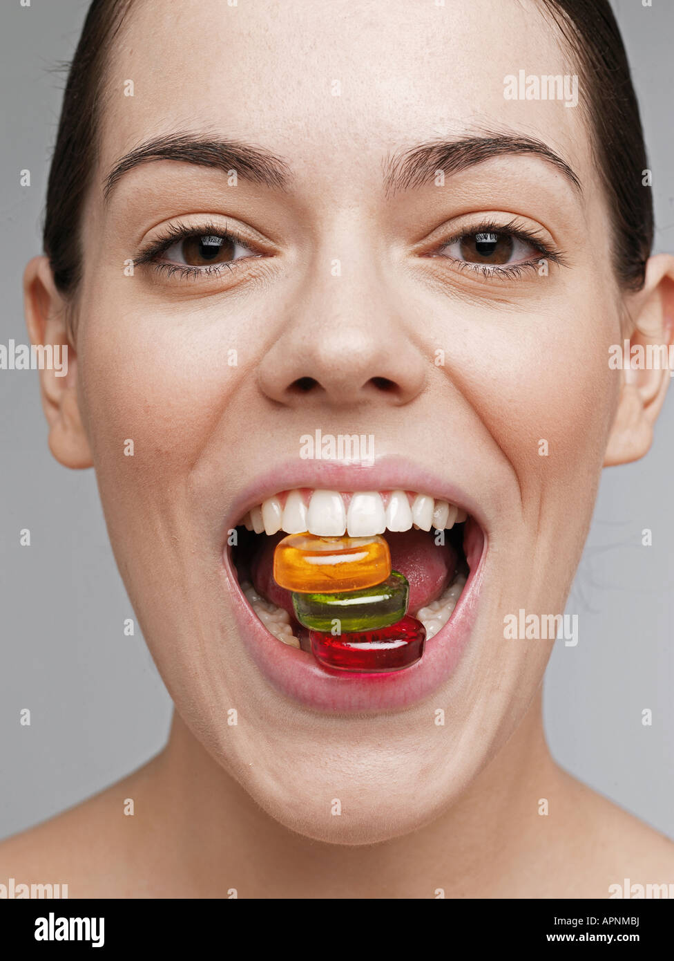 Young woman holding candies in teeth Stock Photo - Alamy