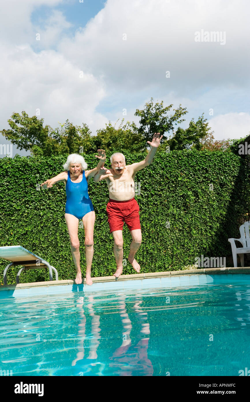 Senior couple jumping into pool Stock Photo - Alamy