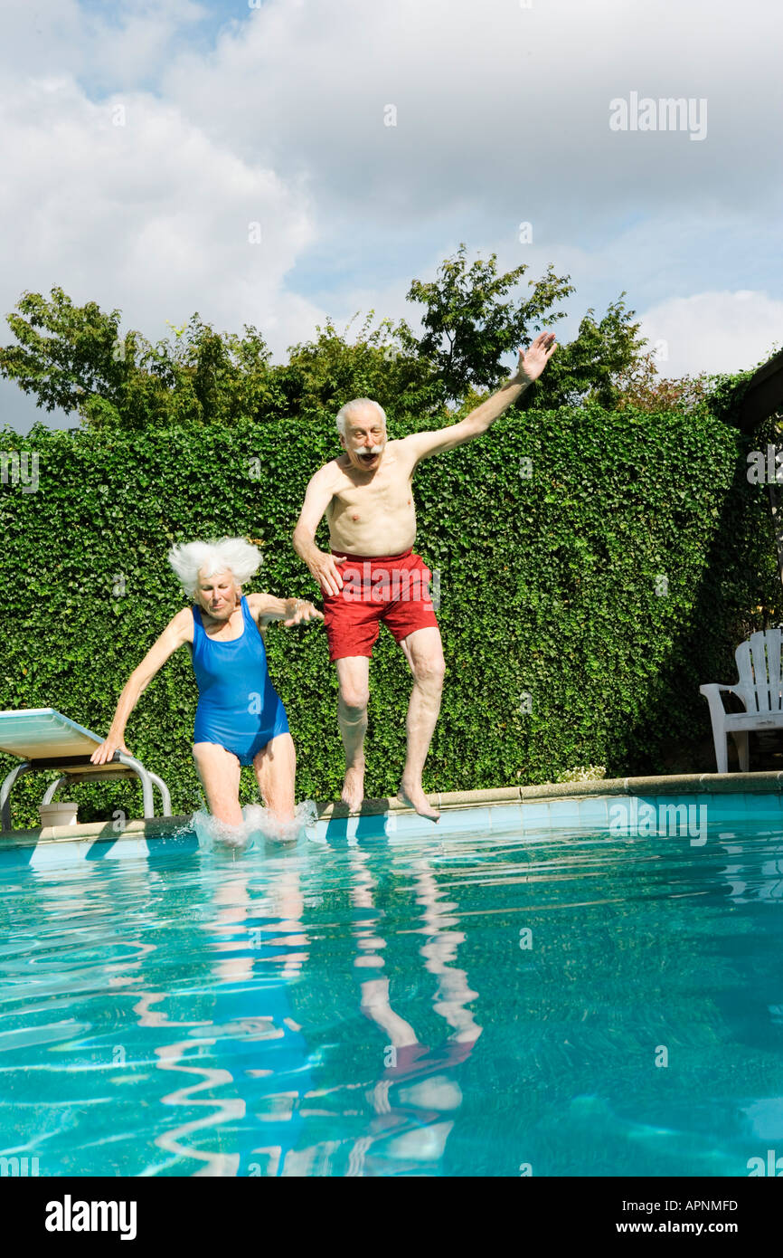Senior couple jumping into pool Stock Photo - Alamy
