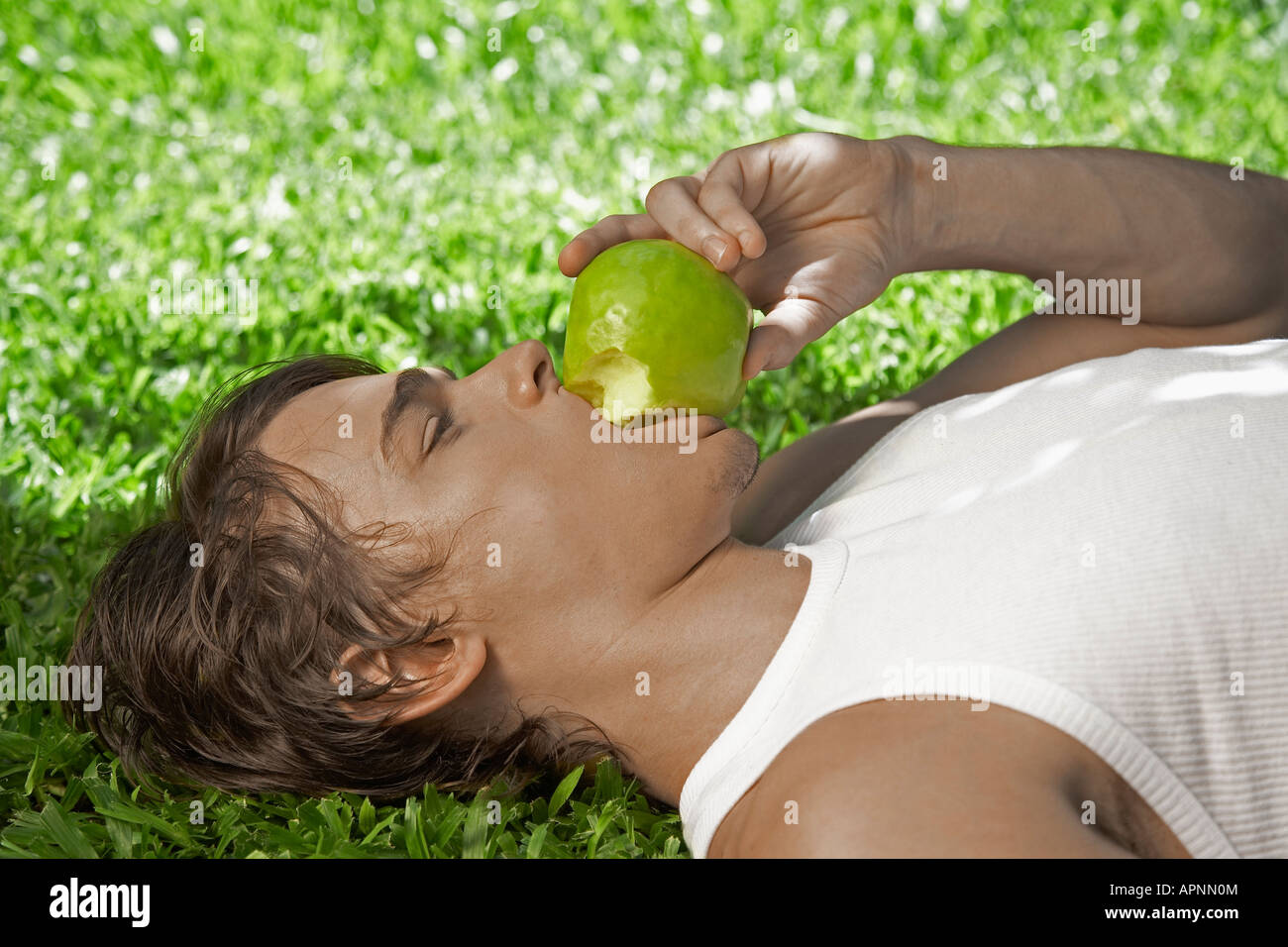 Young Man Eating Apple on Lawn Stock Photo - Alamy