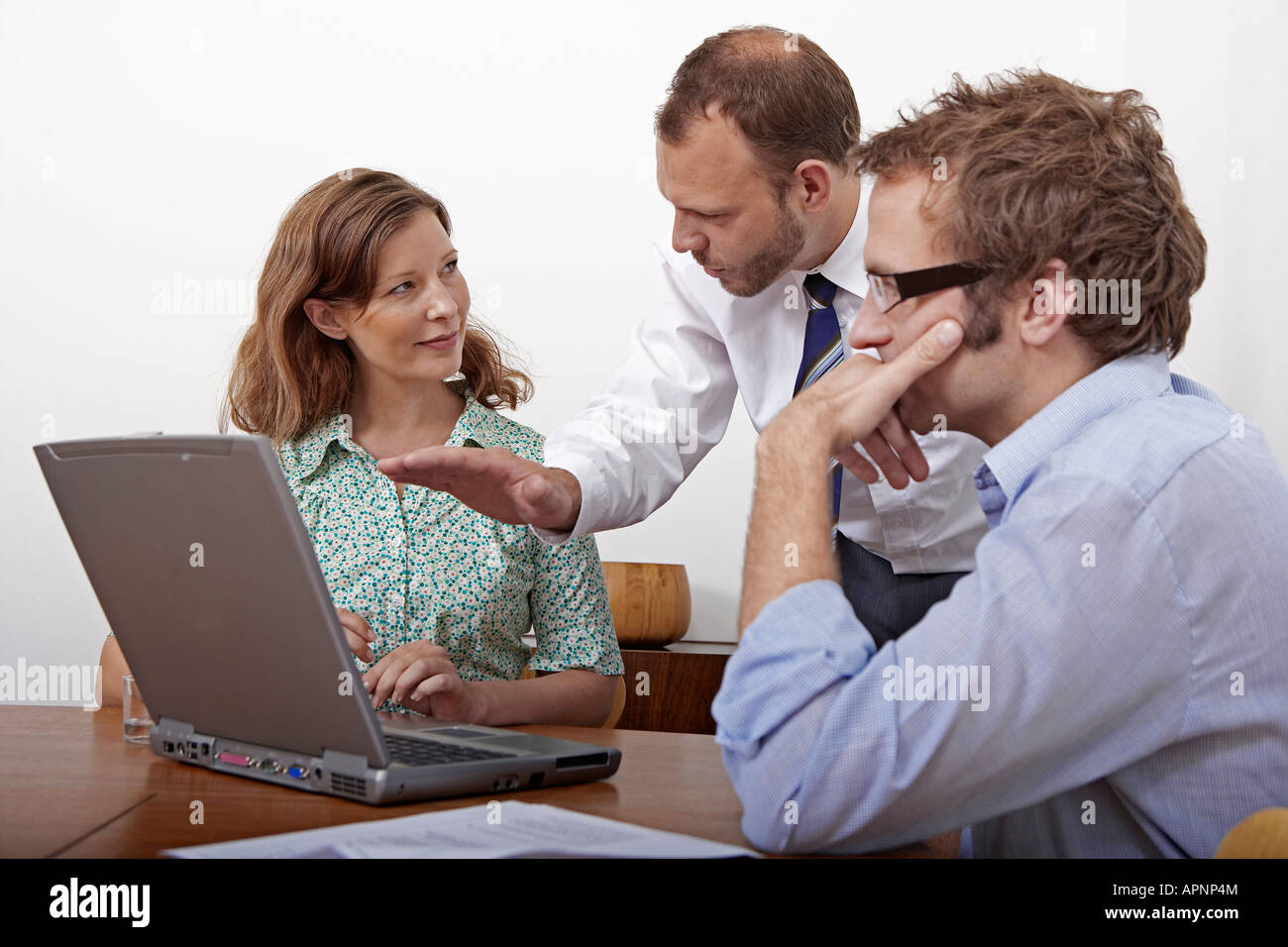 Three Mid Adult People Working on Laptop Stock Photo - Alamy