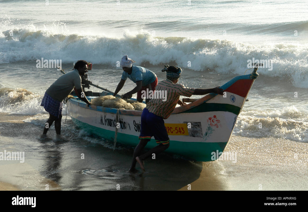 indian fishermen landing their fishing boat in the surf on the beach at ...
