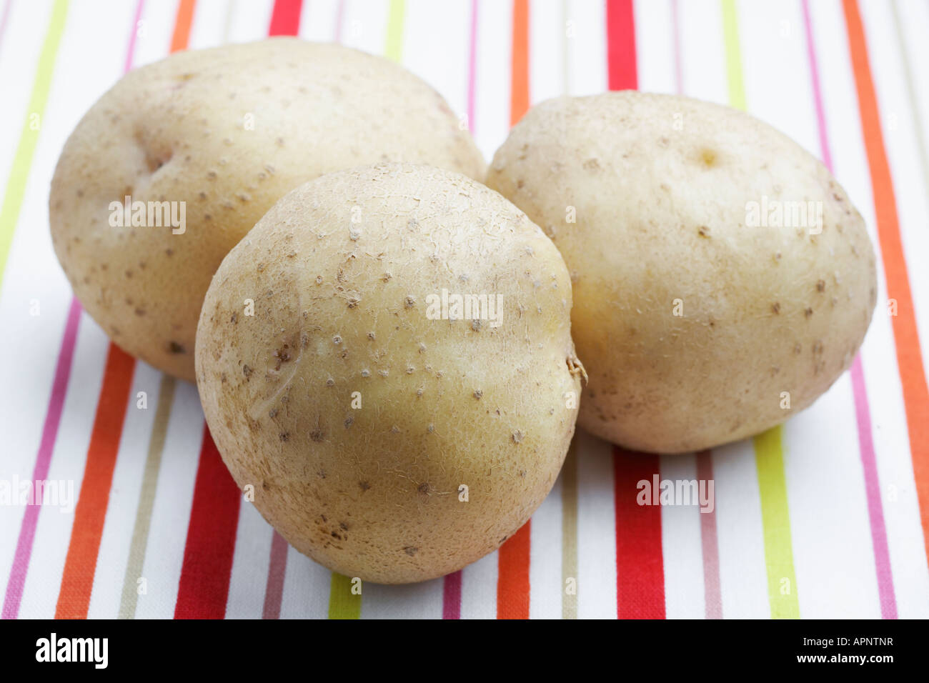 Three potatoes on tablecloth Stock Photo - Alamy
