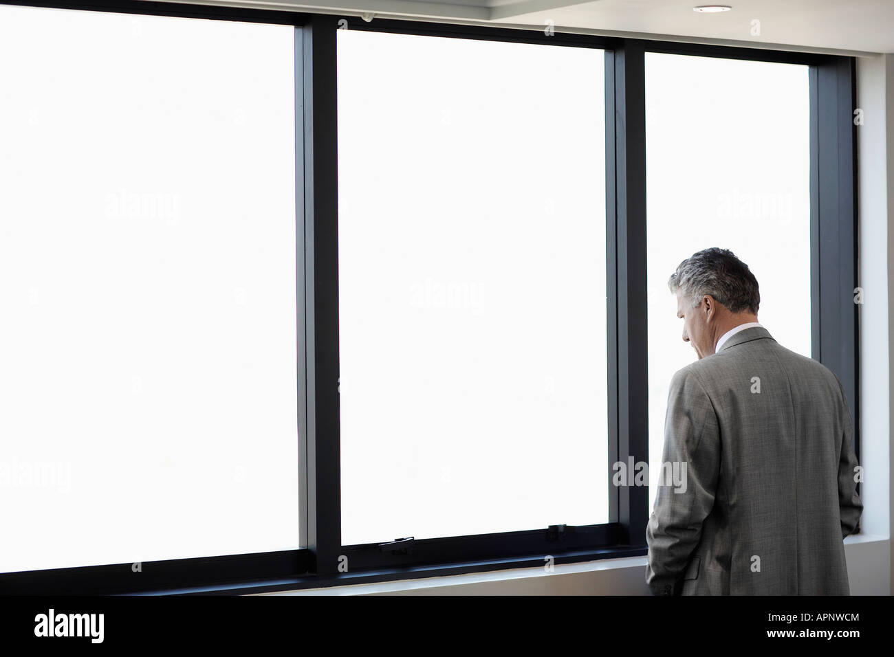 Businessman looking through window Stock Photo - Alamy