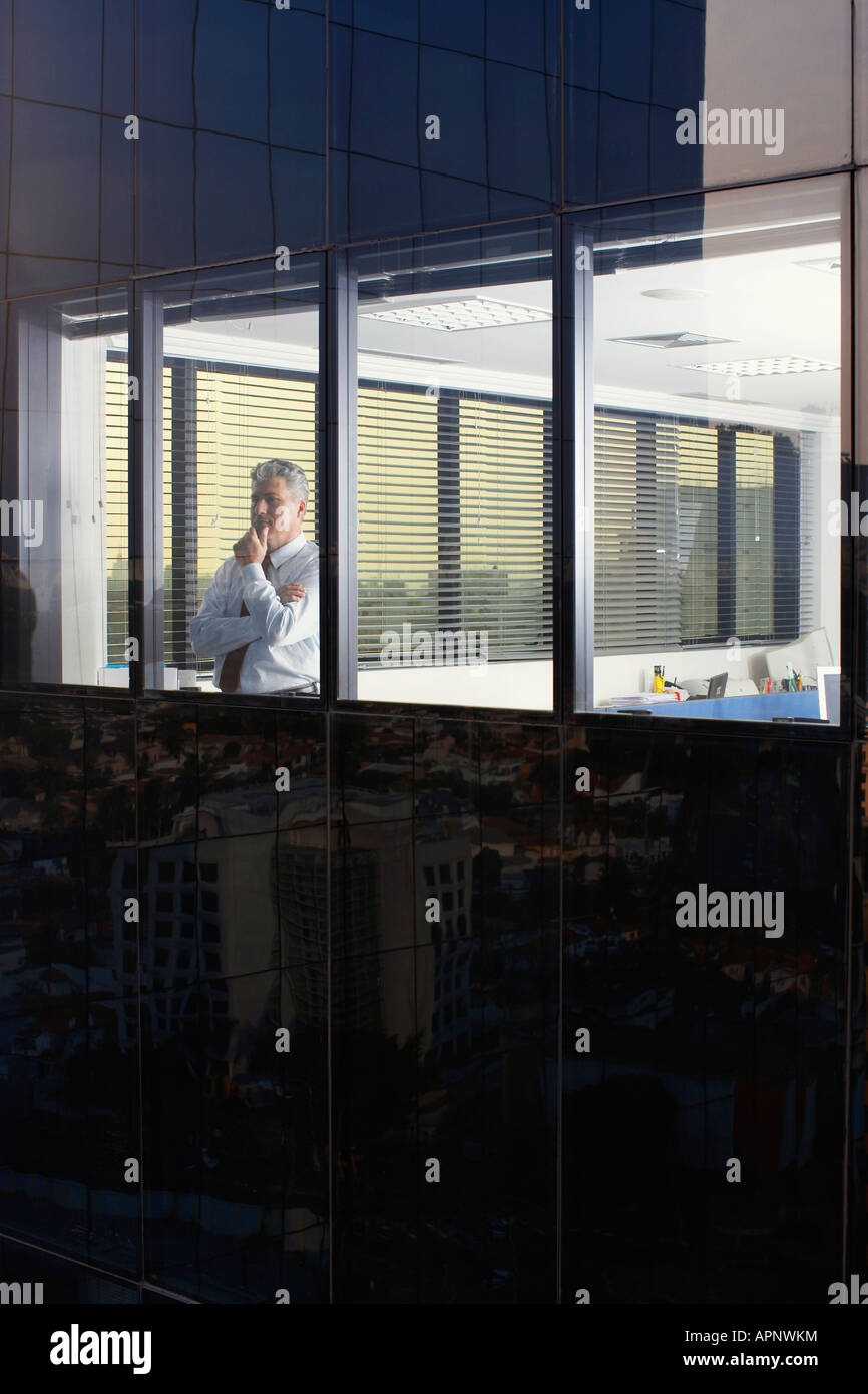 Businessman looking through office window (exterior view Stock Photo ...