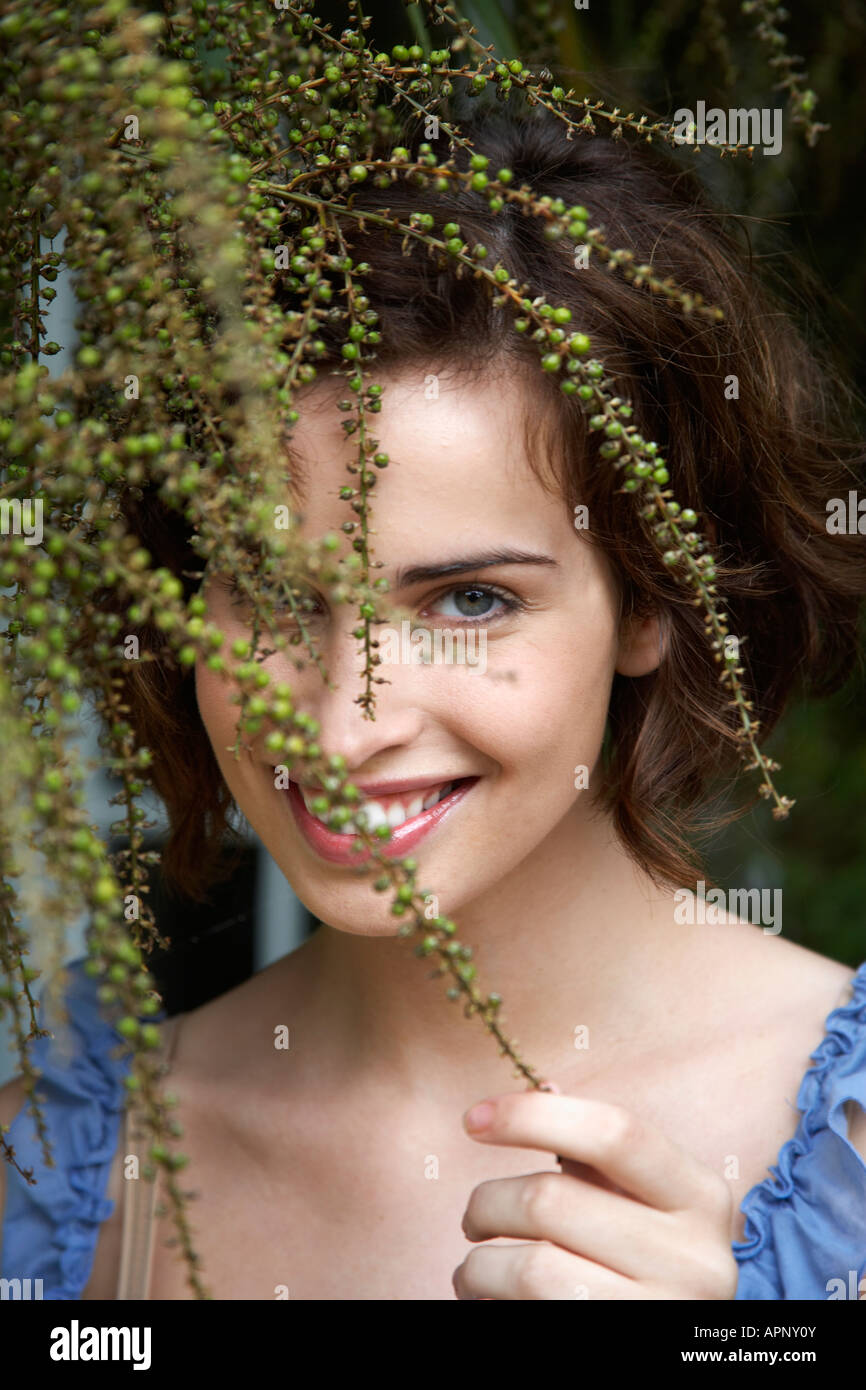 Young woman smiling behind flowers Stock Photo - Alamy