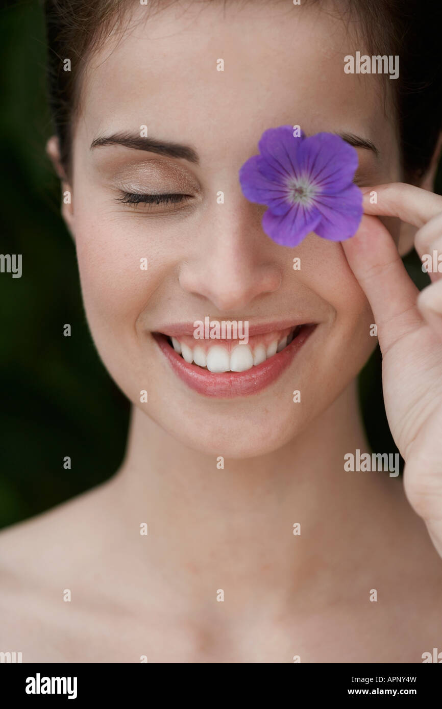 Young woman holding flower over her eye Stock Photo - Alamy