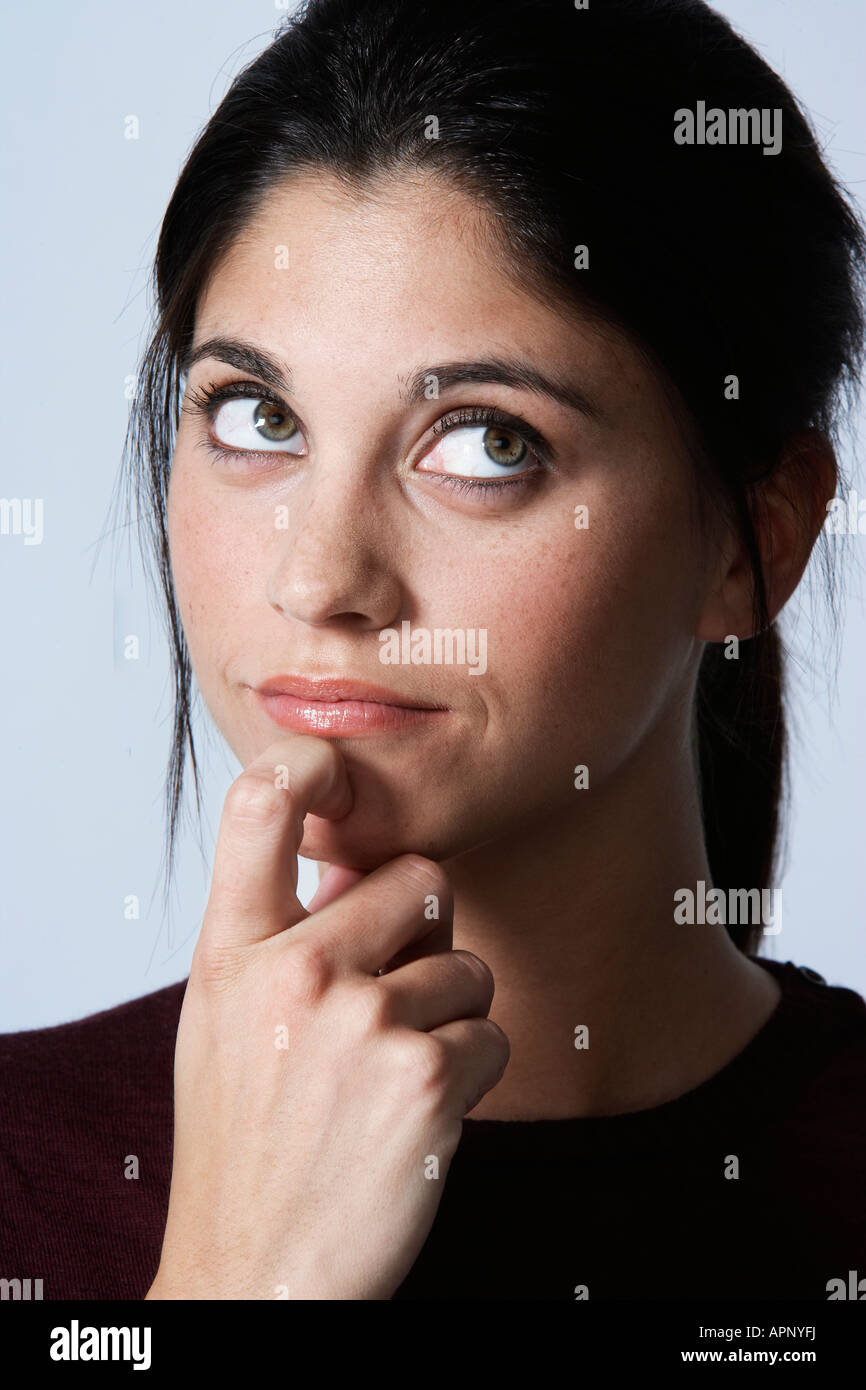 Young woman thinking with finger on chin Stock Photo - Alamy