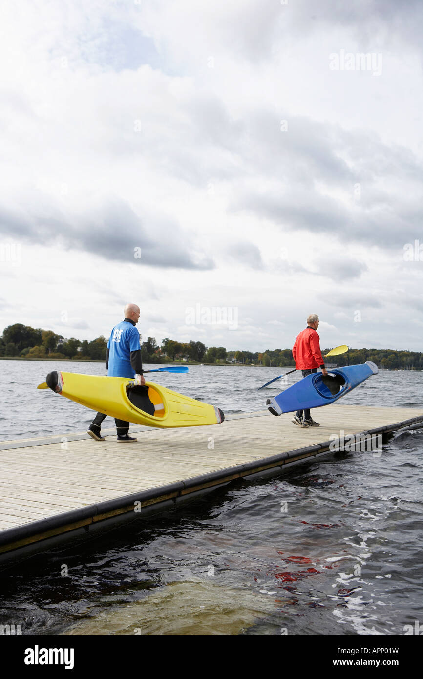 Two senior men carrying kayaks Stock Photo - Alamy