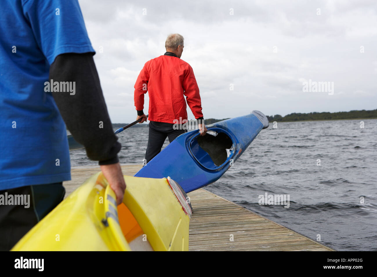 Two senior men carrying kayaks Stock Photo - Alamy