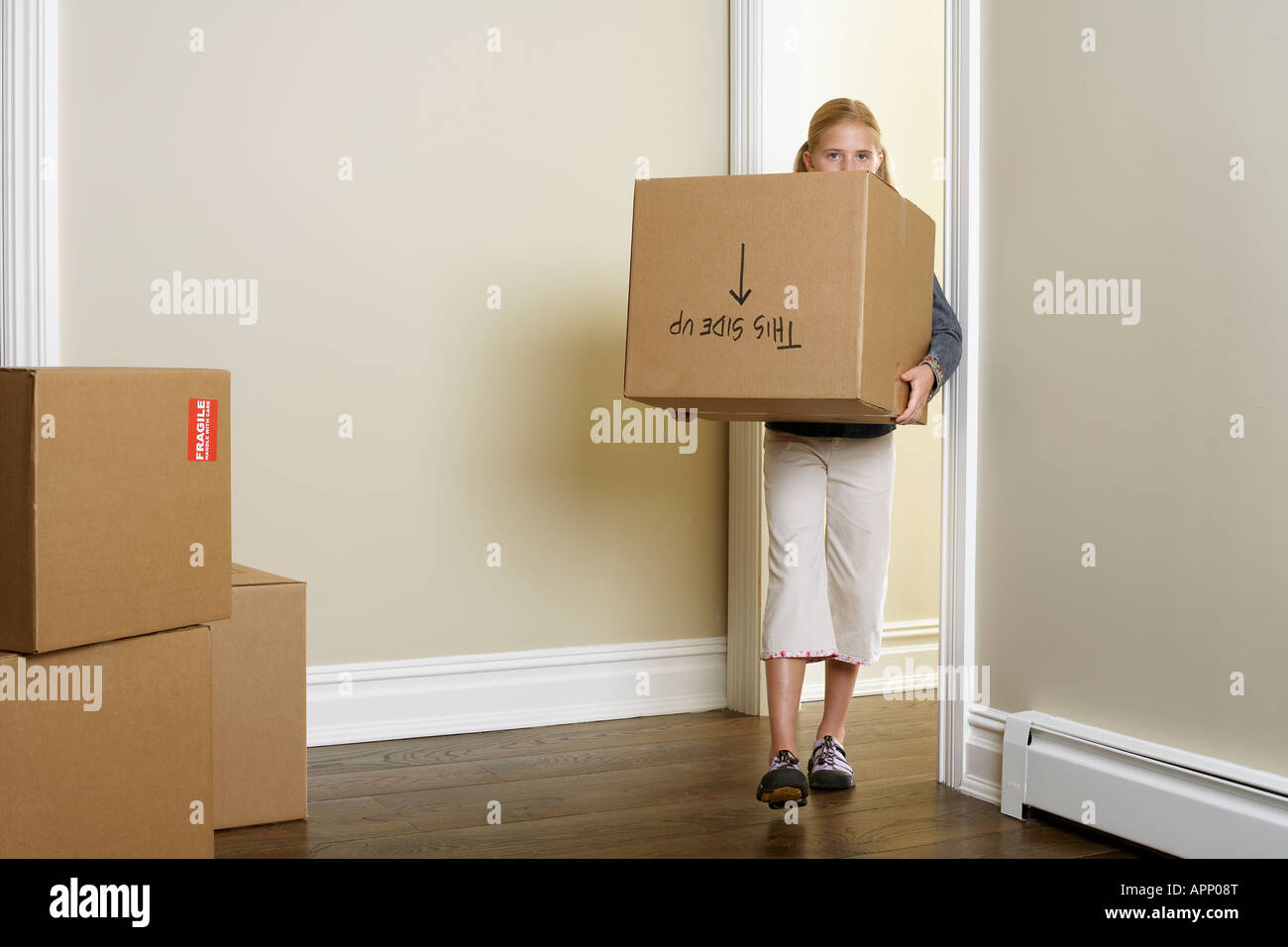 Pre-adolescent girl carrying box upside down Stock Photo - Alamy